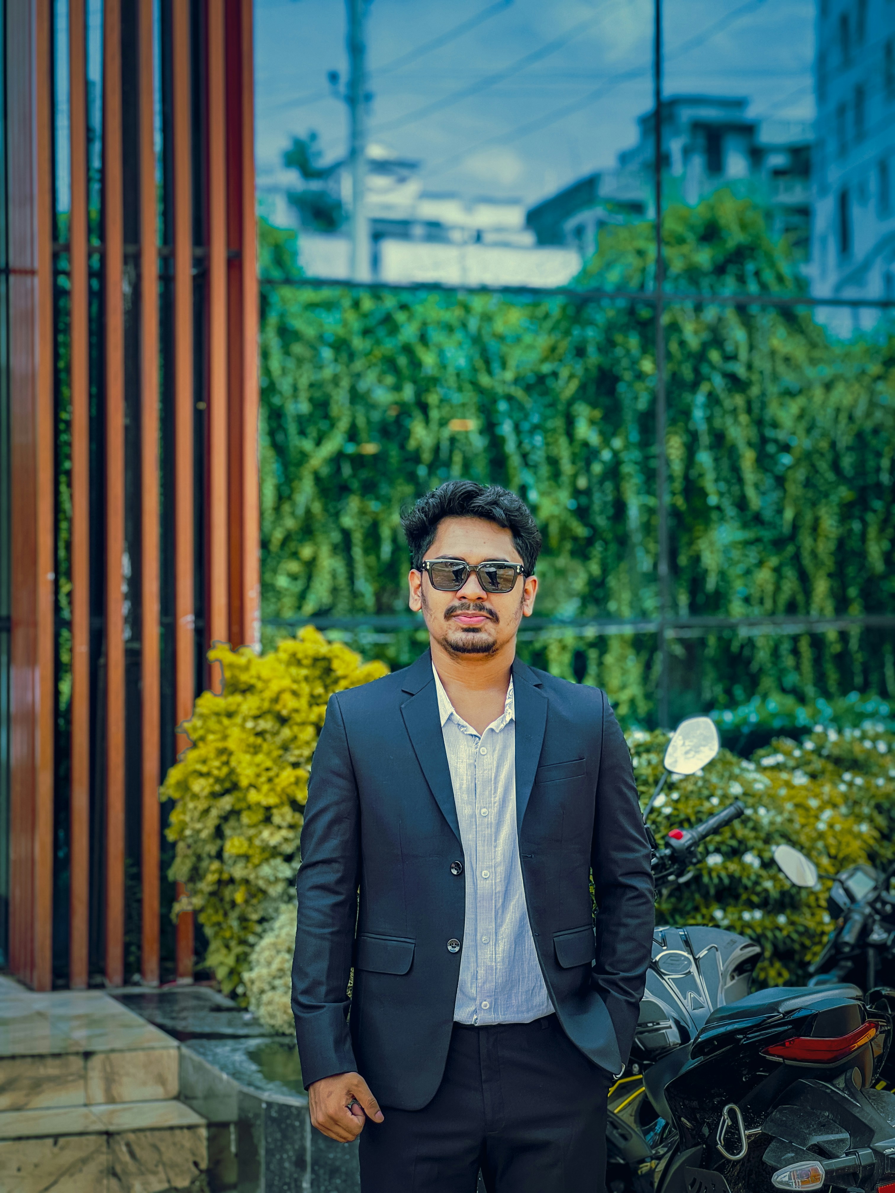 Portrait in a corporate courtyard: a man in a navy suit under glassy backdrop