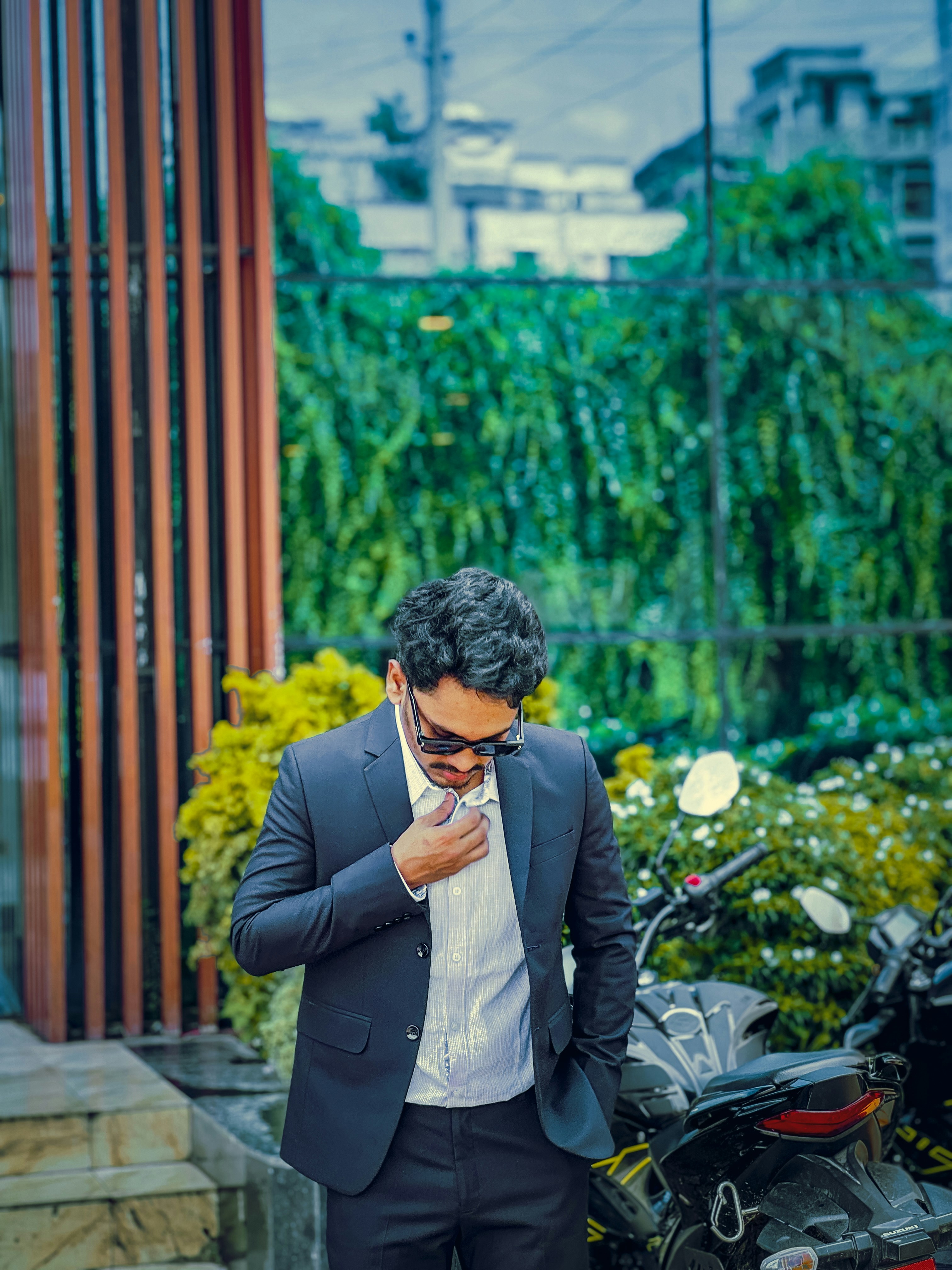 Dapper Moment: Adjusting His Tie Under city-green Backdrop
