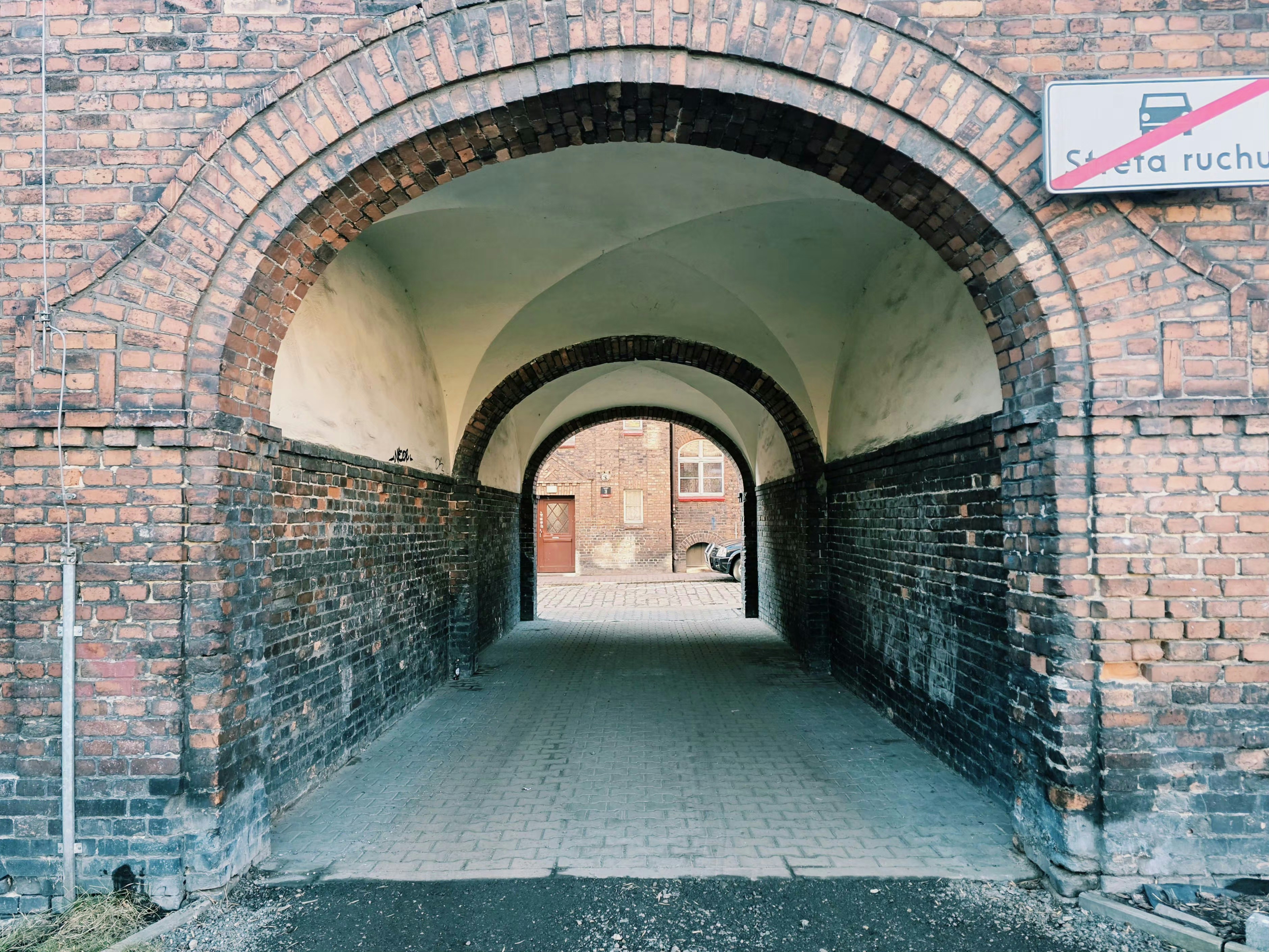 Archway Corridor: The Long Brick Tunnel Framing a Quiet Street