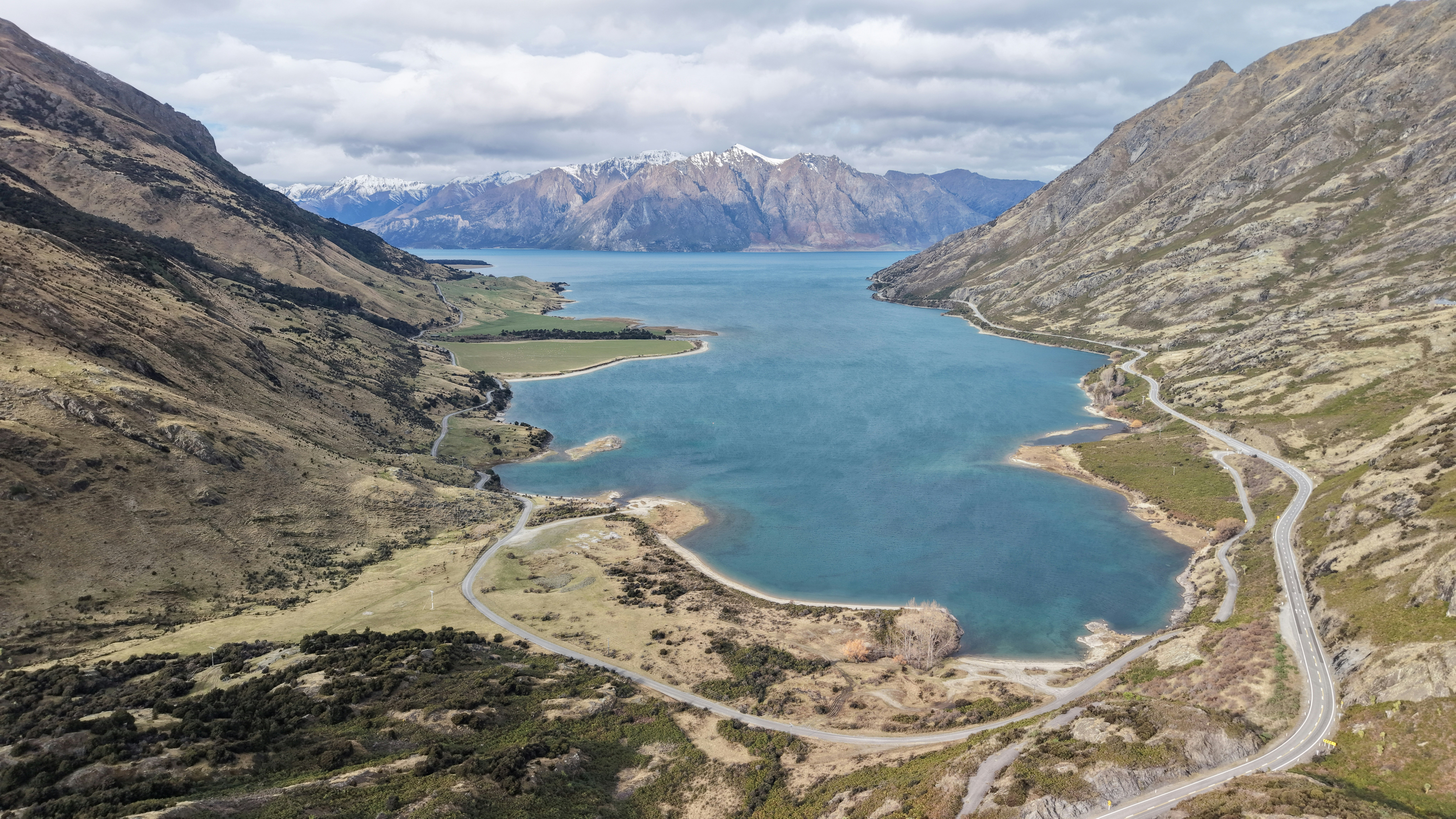 Aerial serpentine road embracing a mountain lake panorama