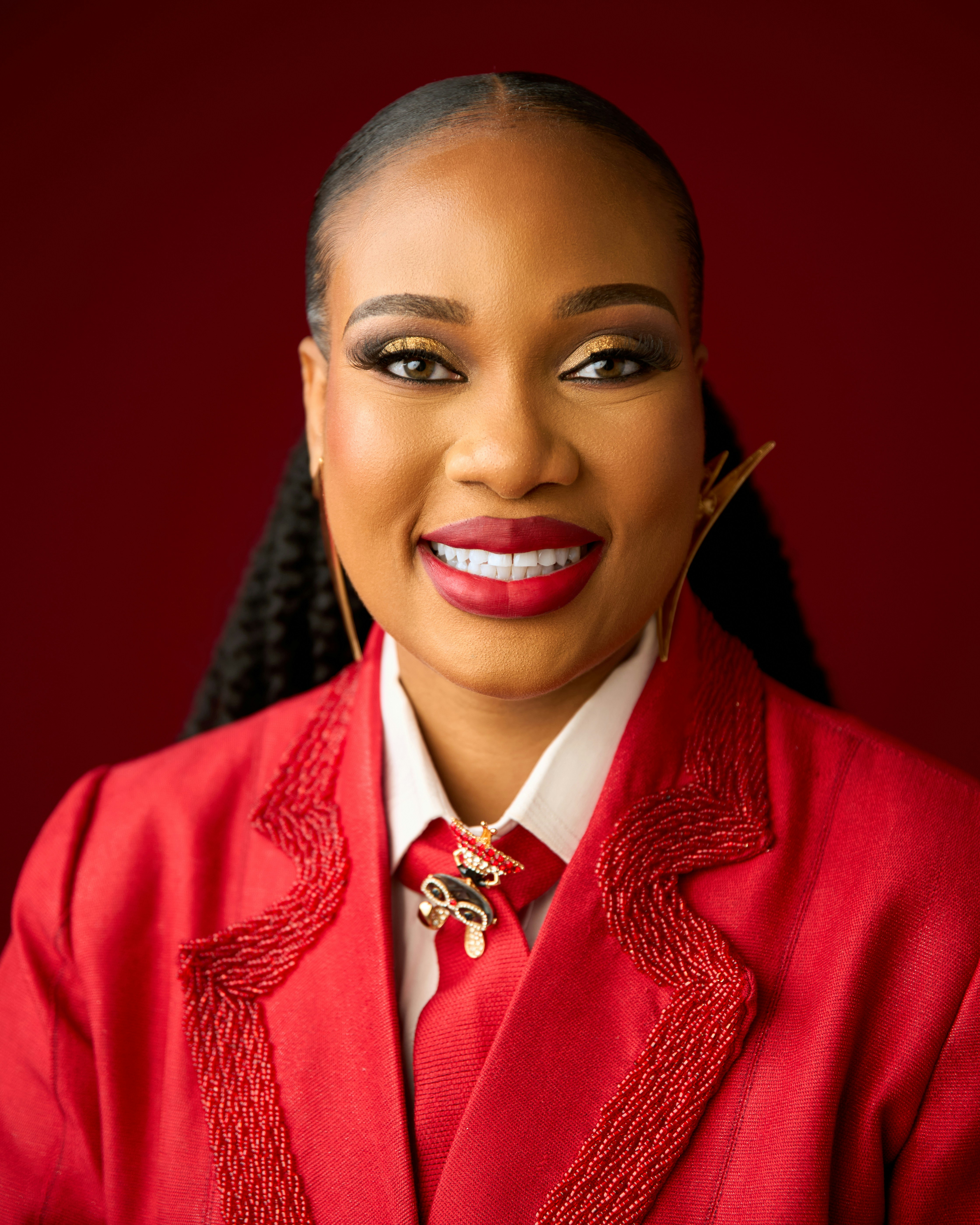 A woman in a red suit smiling brightly.