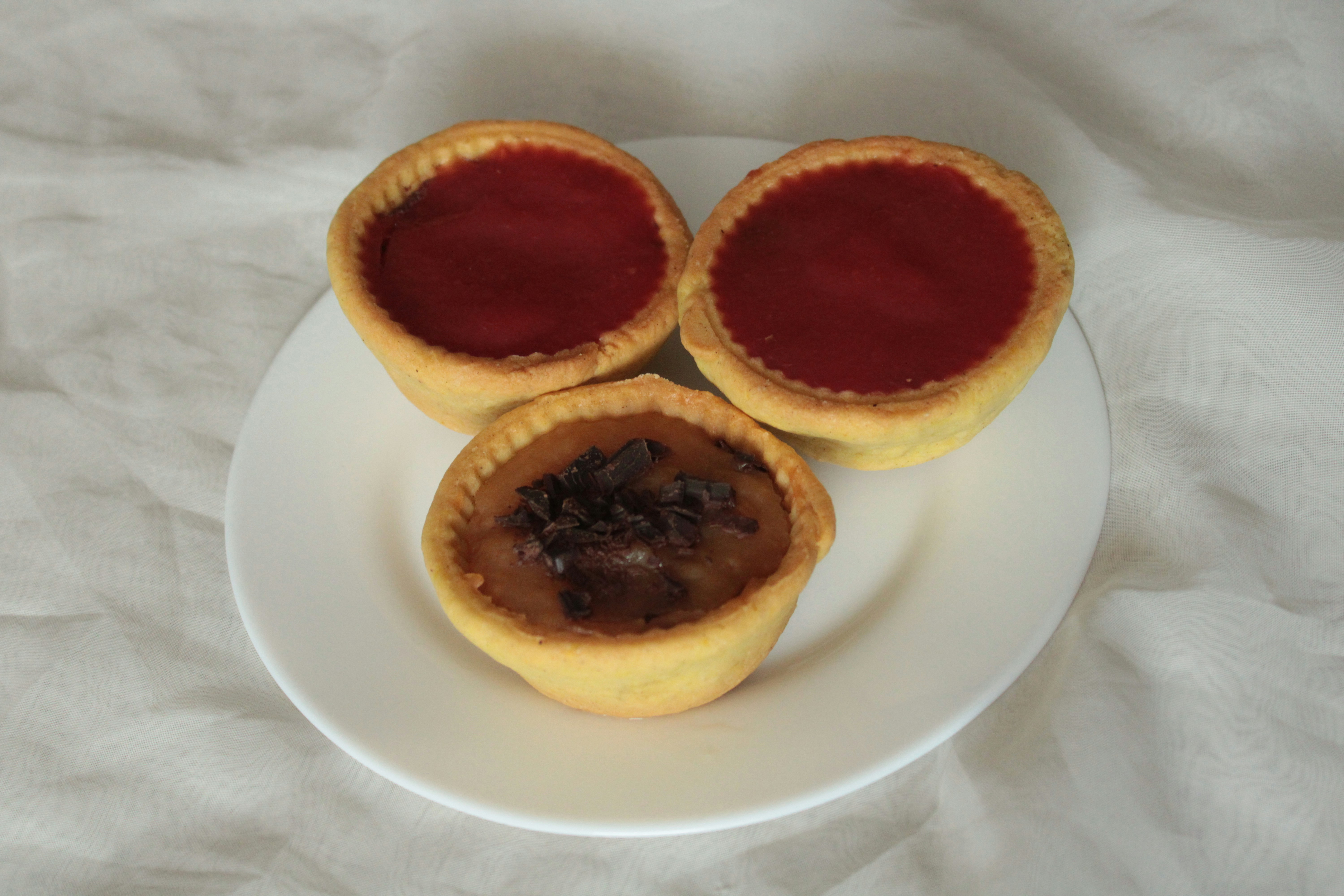 Three Mini Tarts on a White Plate: Red Tops and Caramel Center