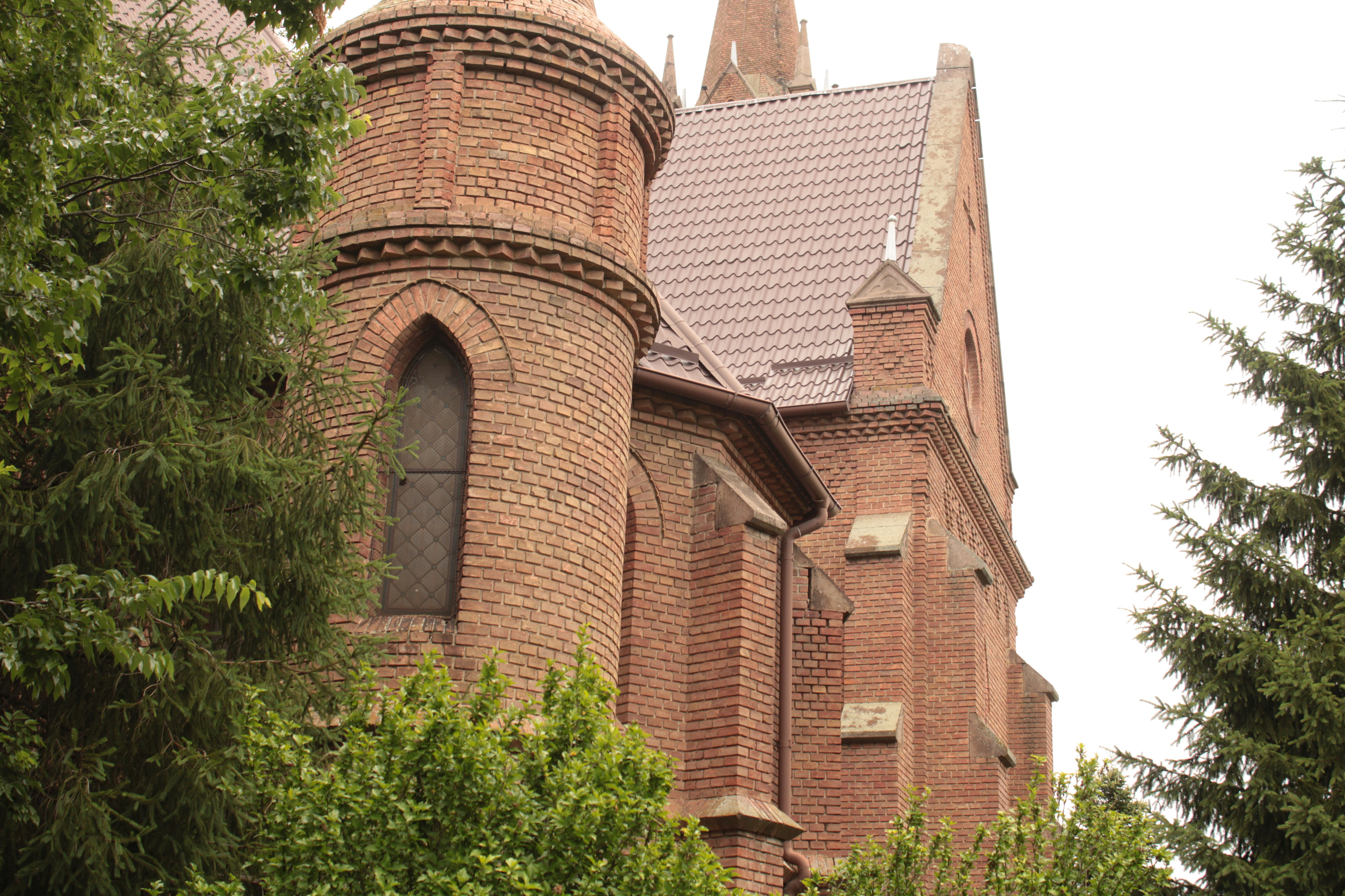 Brick Gothic: A Corner Perspective of a Towered Church Surrounded by Greenery