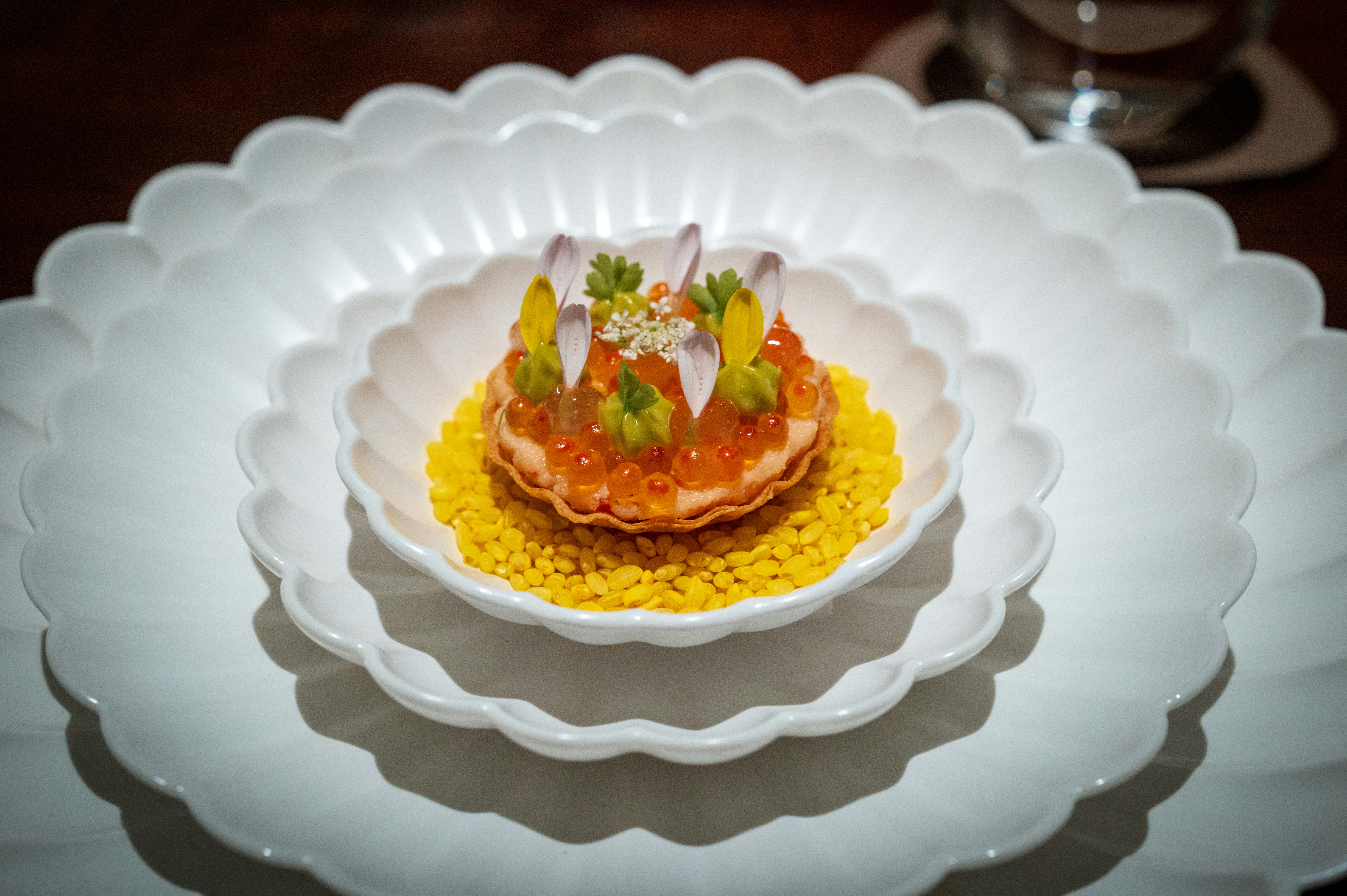 Exquisite culinary dish with roe, edible flowers, and yellow garnish.