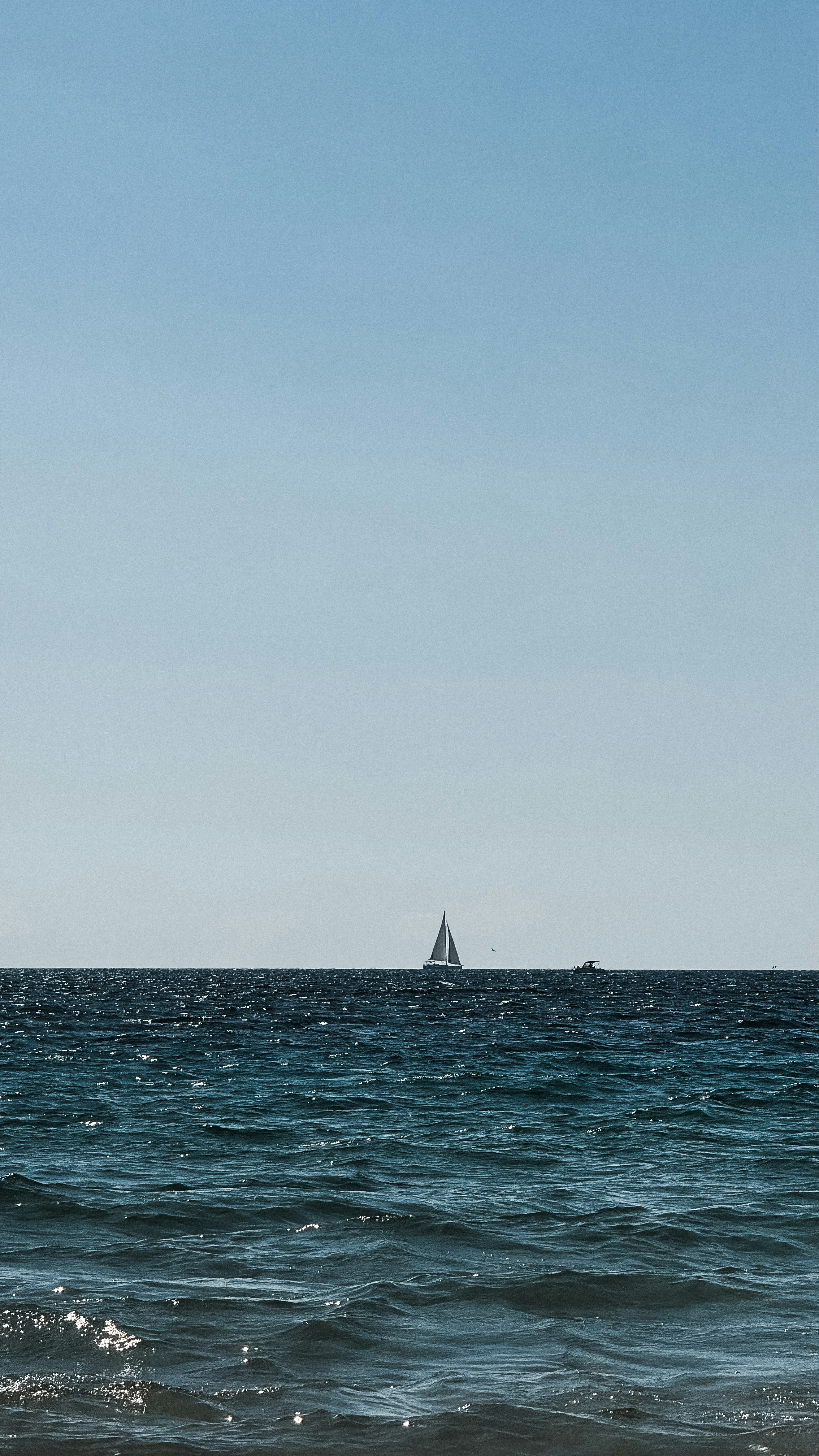 Sea Breeze on the Horizon: A Lone Sailboat in Quiet Light