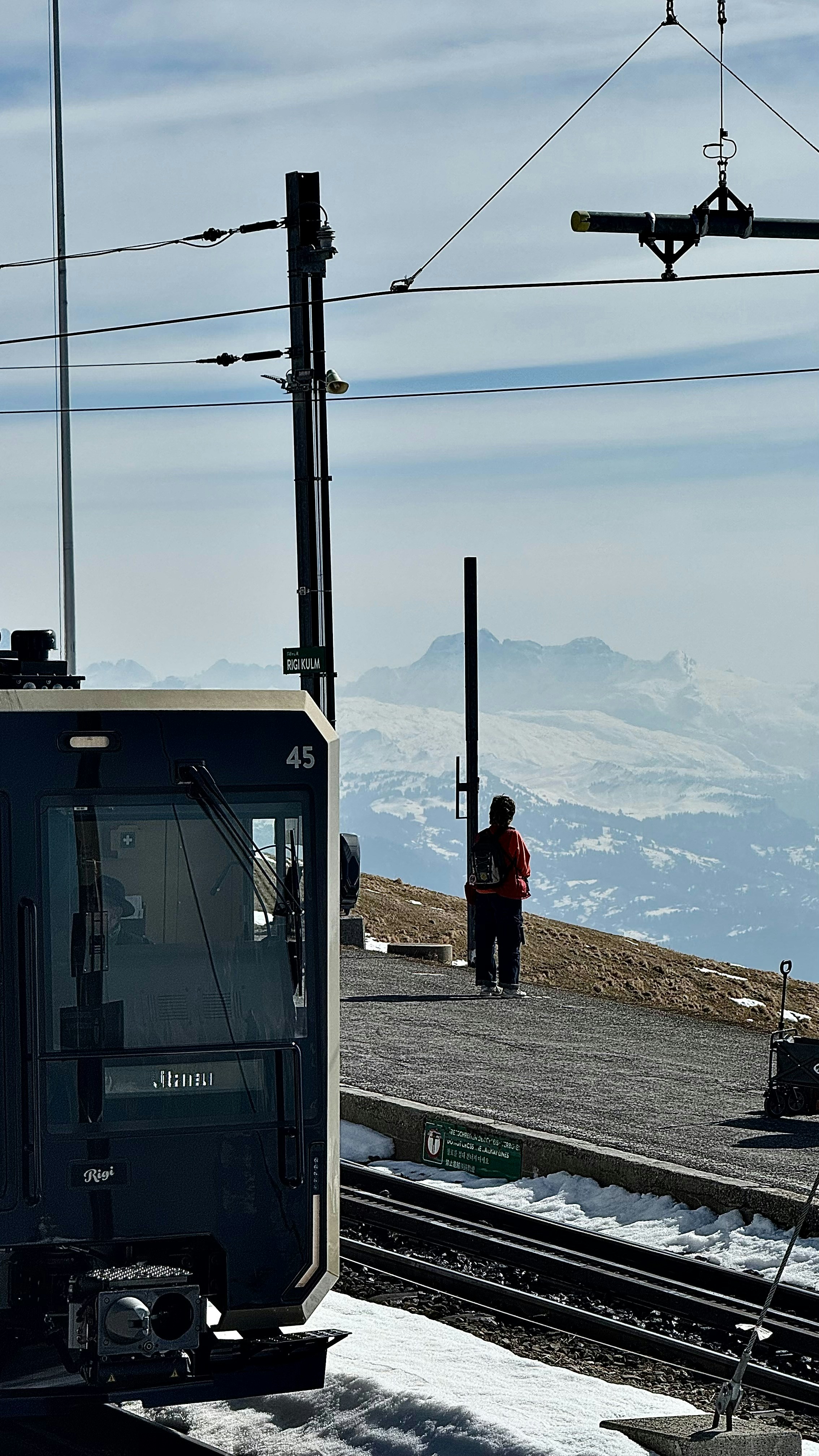 Snow-capped ridge reveals a lonely hiker beside a tram at alpine altitude