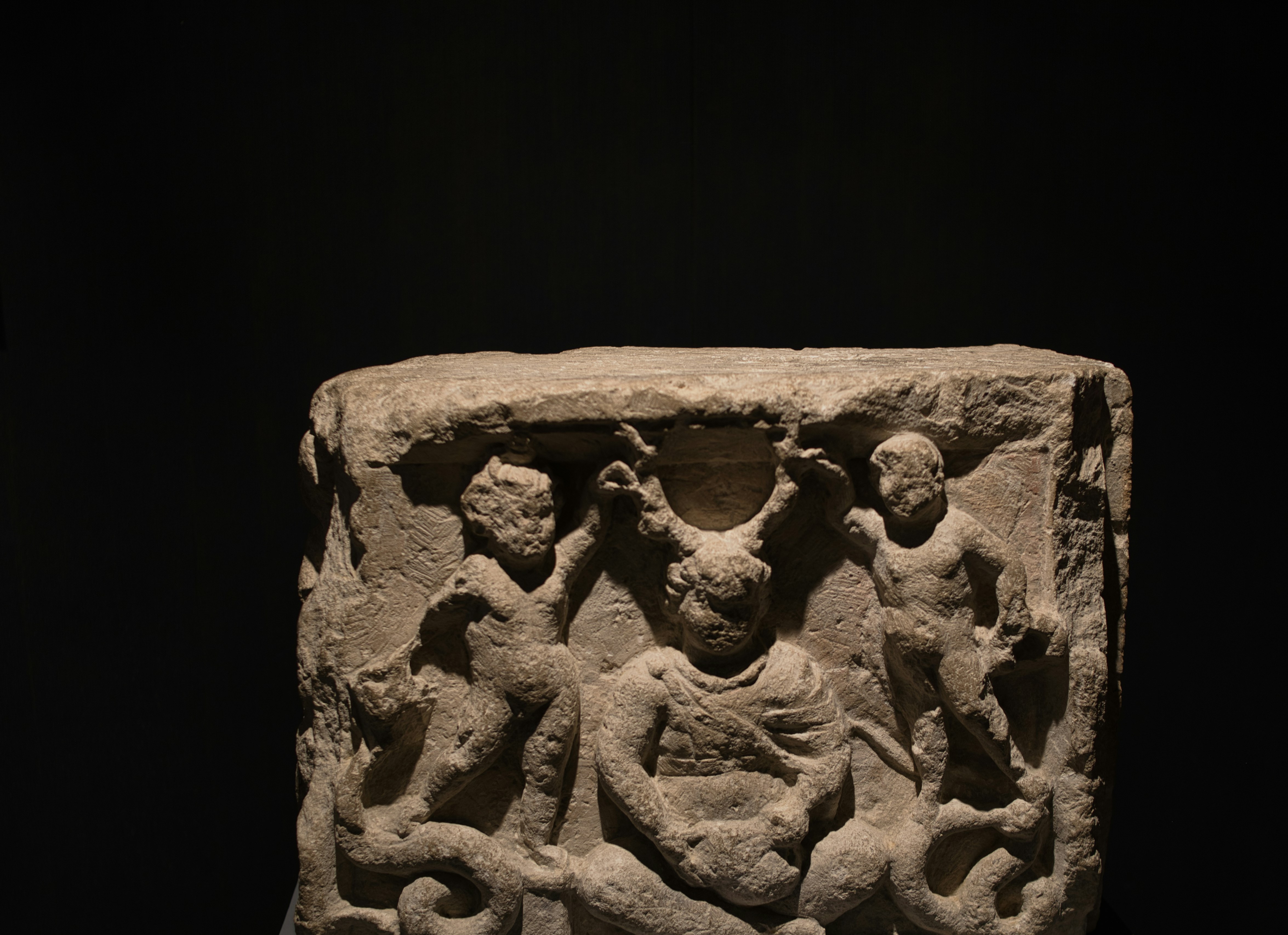 Relief of Attentive Figures: A Stone Carving Emerges from Darkness