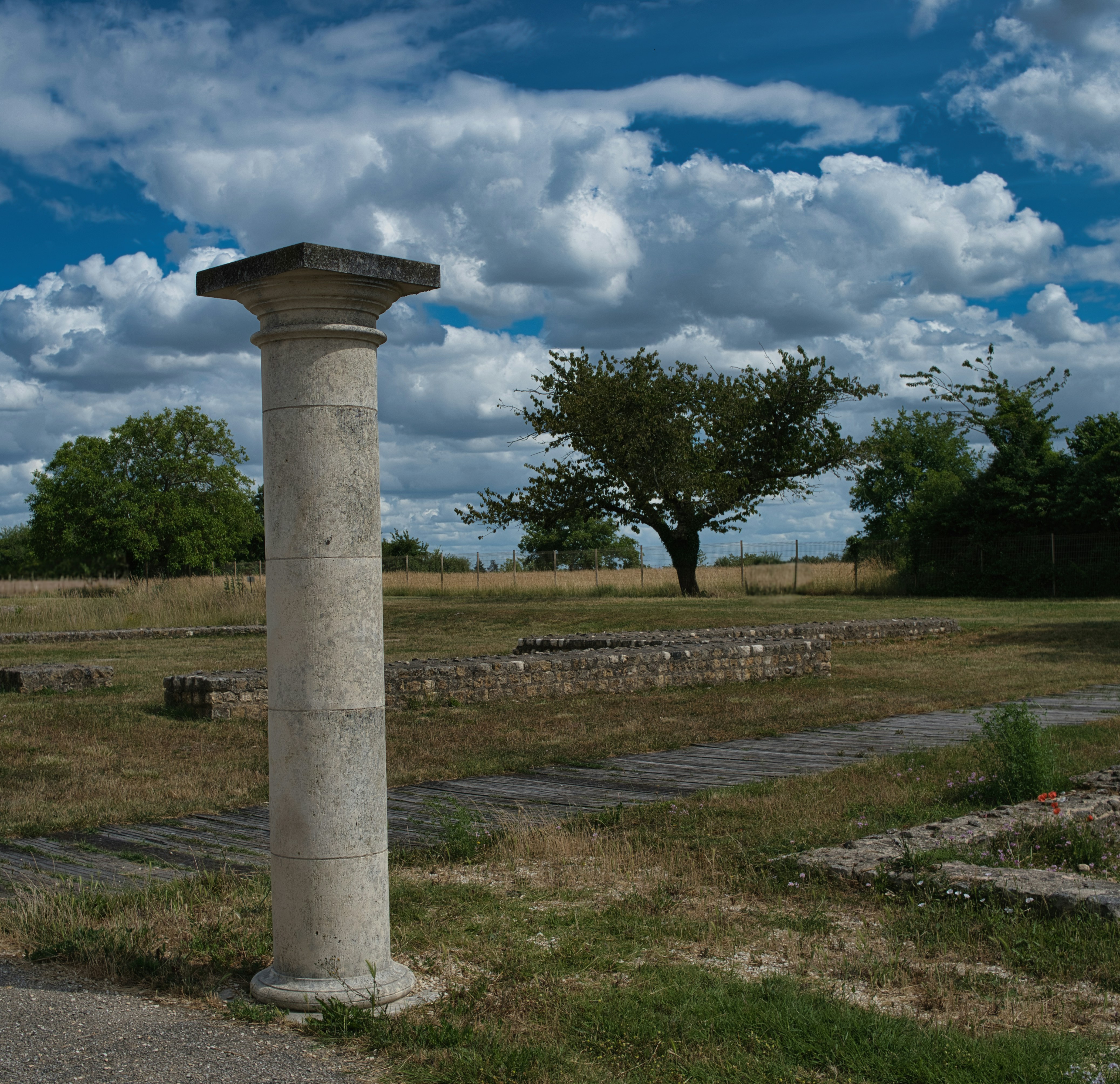 Ancient Column in Open Field under a Dramatic Sky