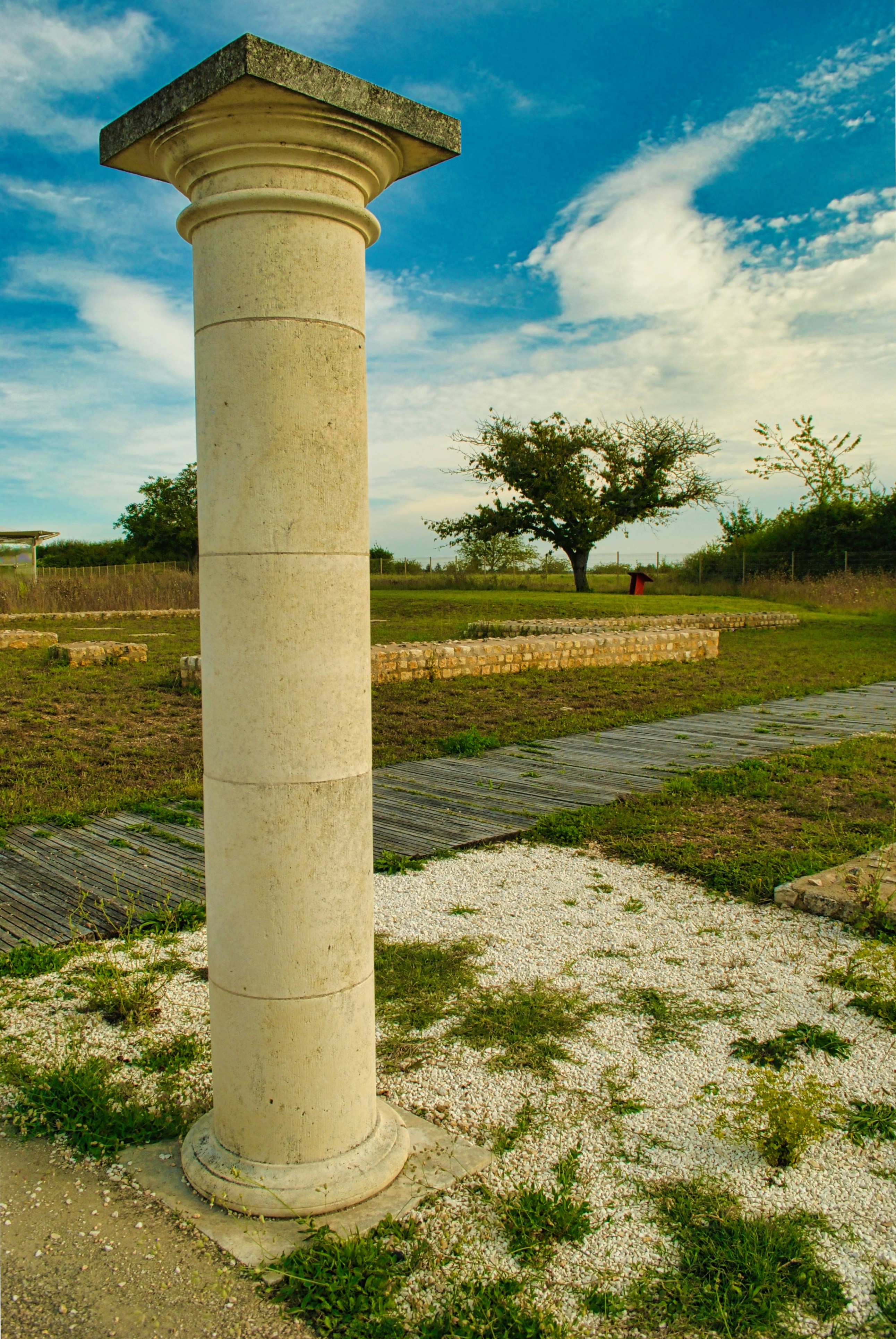 Stone Column in a Sunny Park Framing a Distant Tree