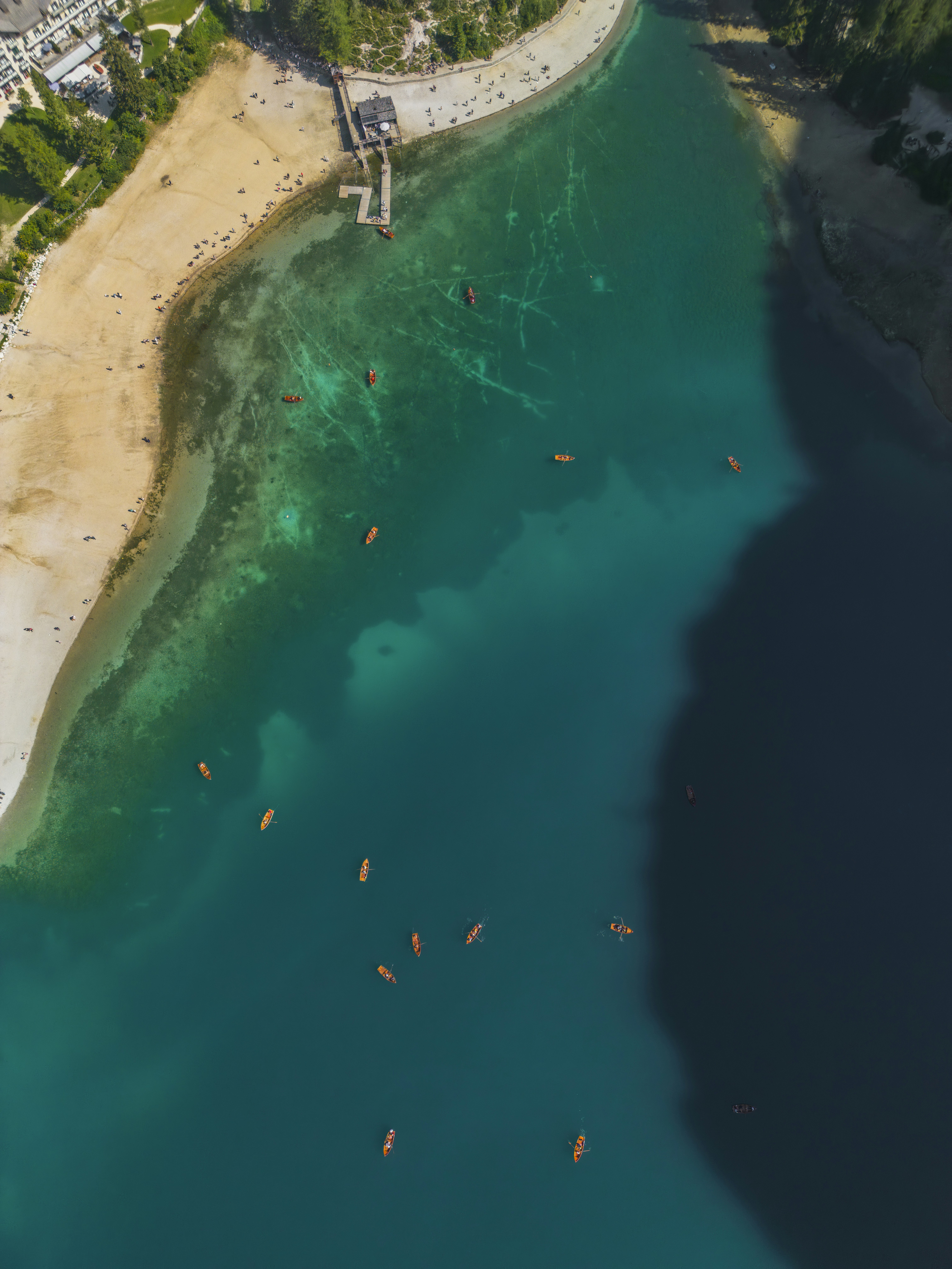 Aqua Tides and Shoreline: Drone View Over a Sunlit Beach Collecting Sea Kayaks