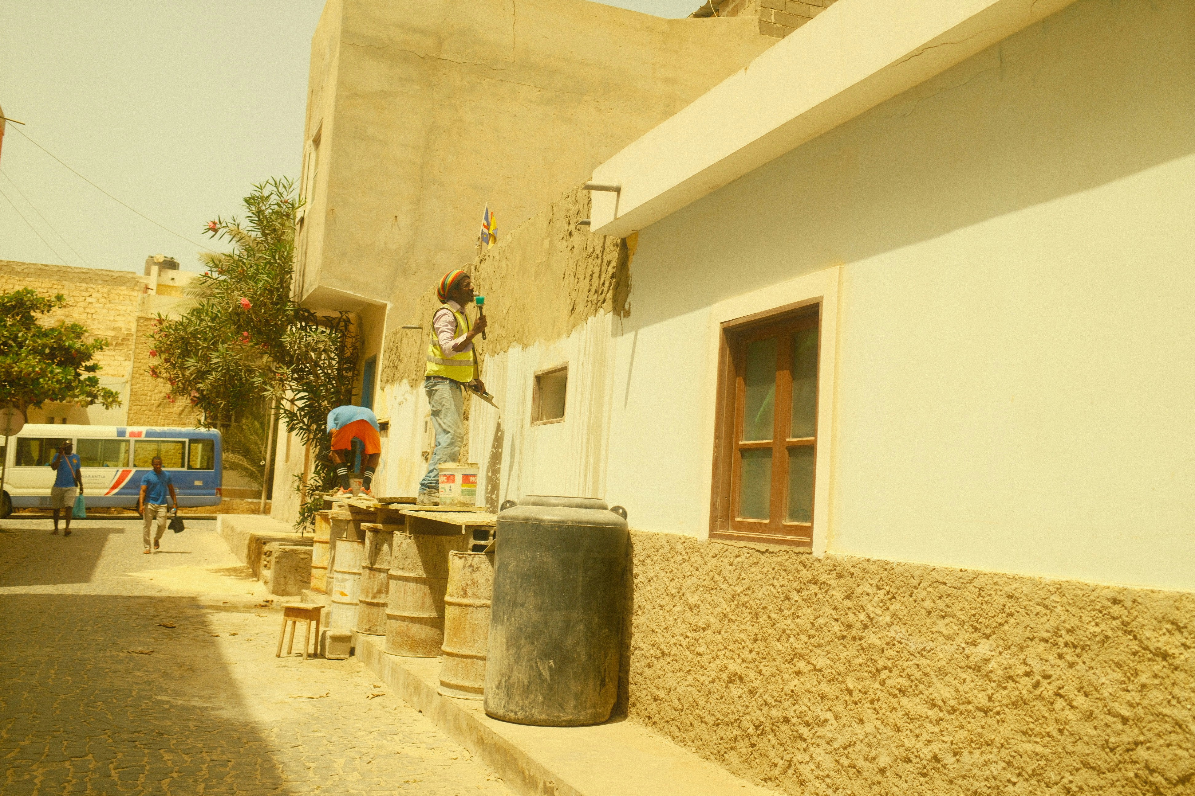 Sunlit Street Work: Painter on the Courtyard Wall