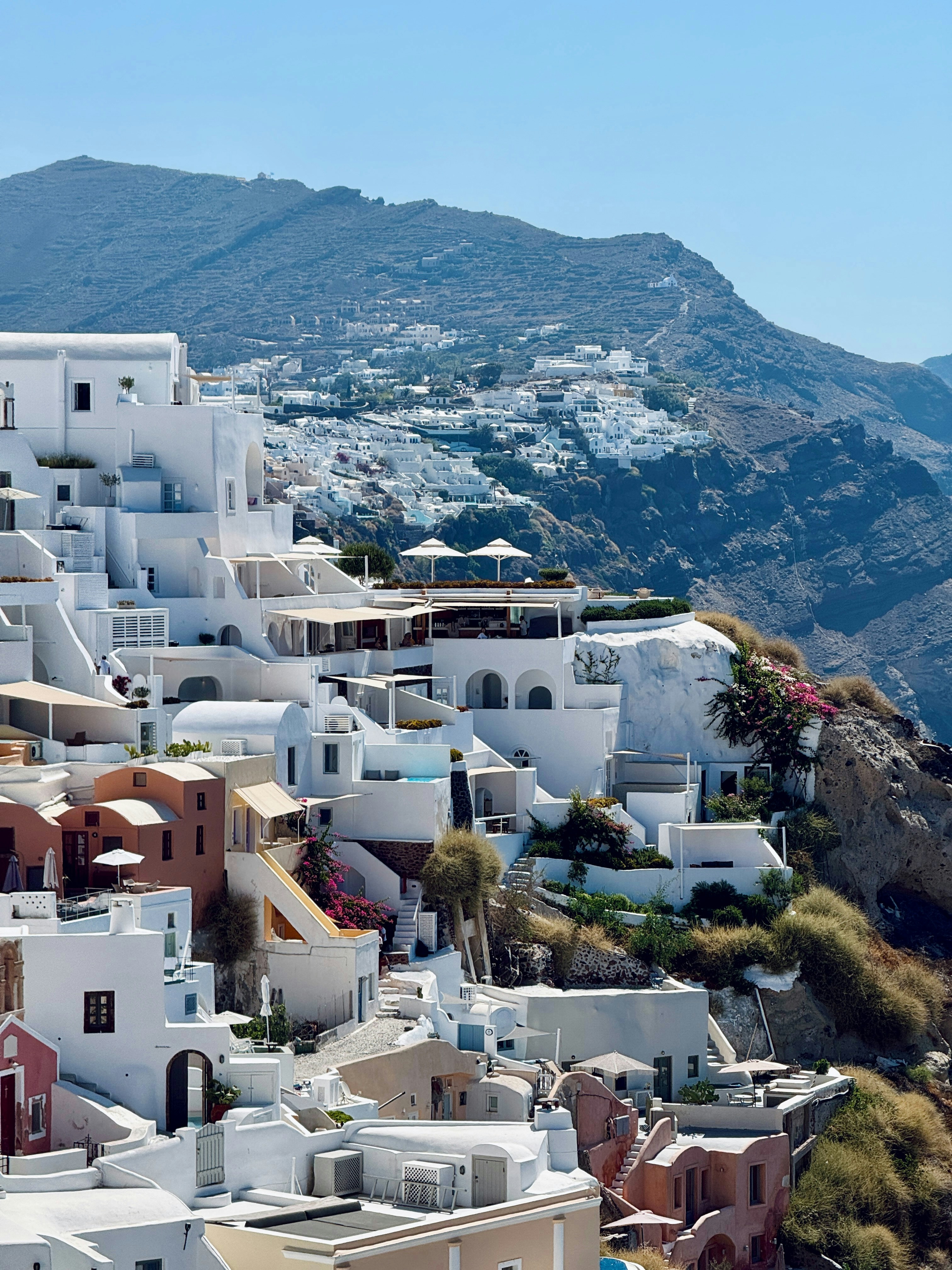 Whitewashed terraces cascade along a sunlit cliffside in Santorini