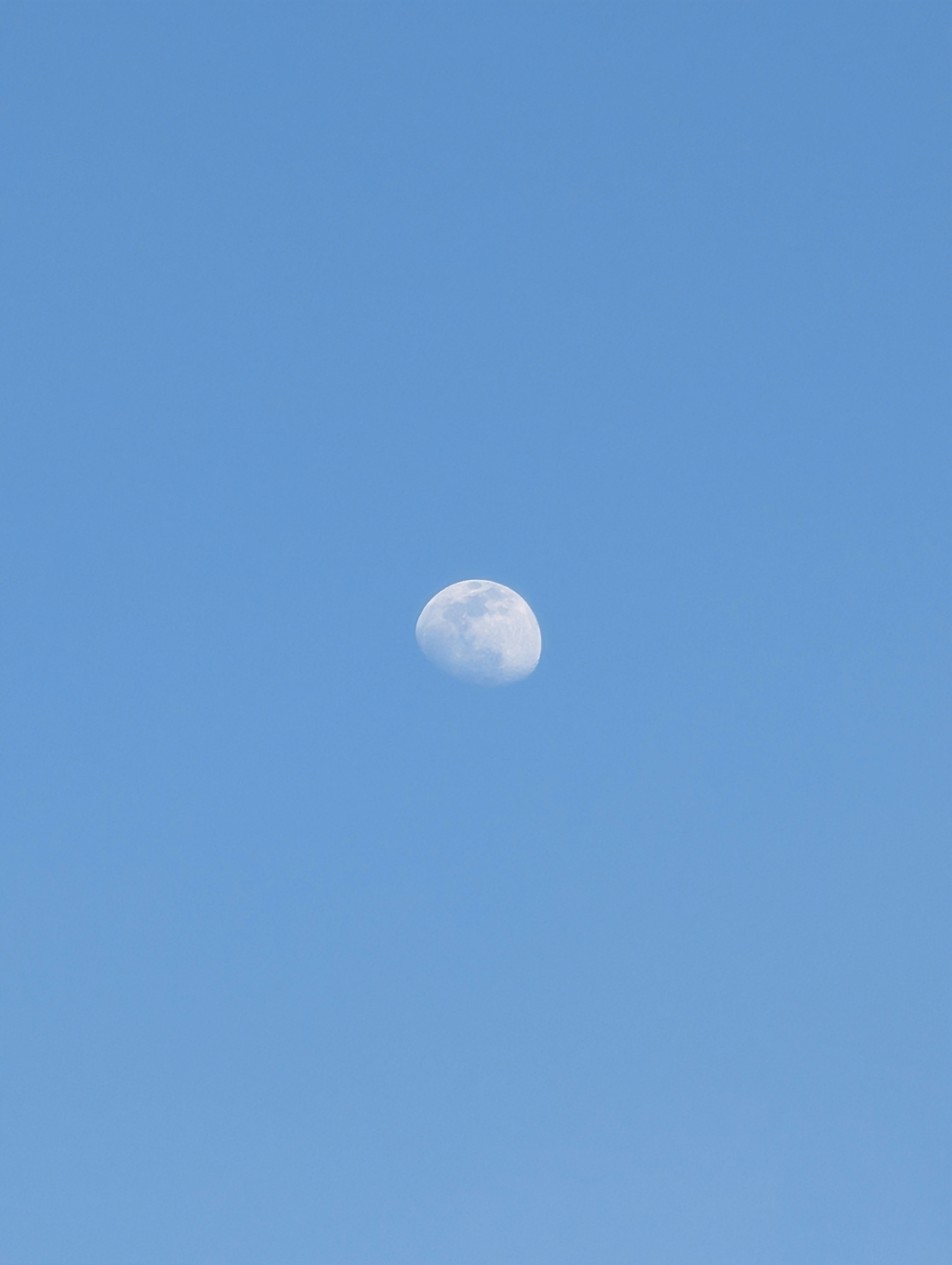 Soft blue sky with a lone moon in daylight, centered and minimalistic.