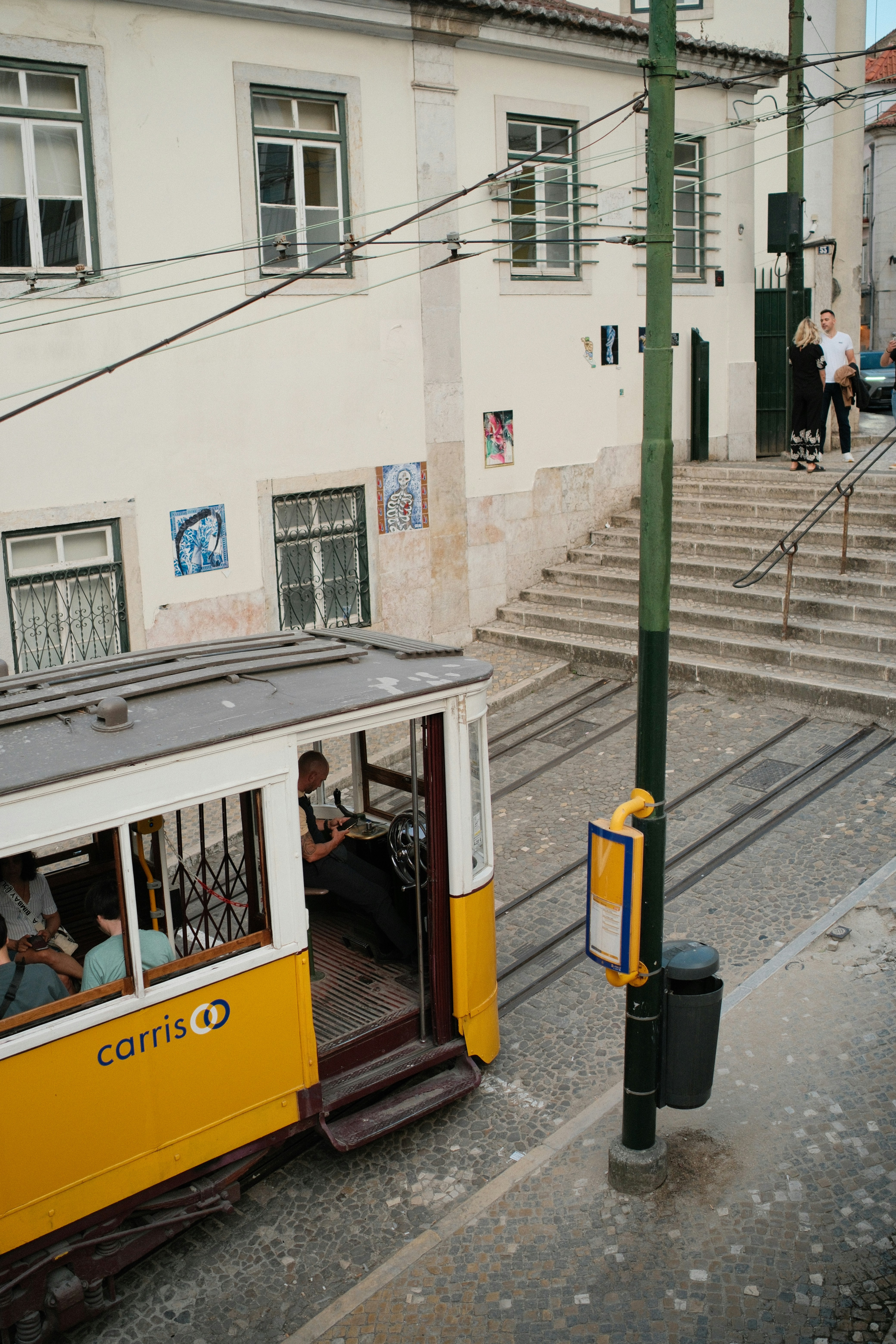 Yellow tram at the edge of a sunlit Lisbon street