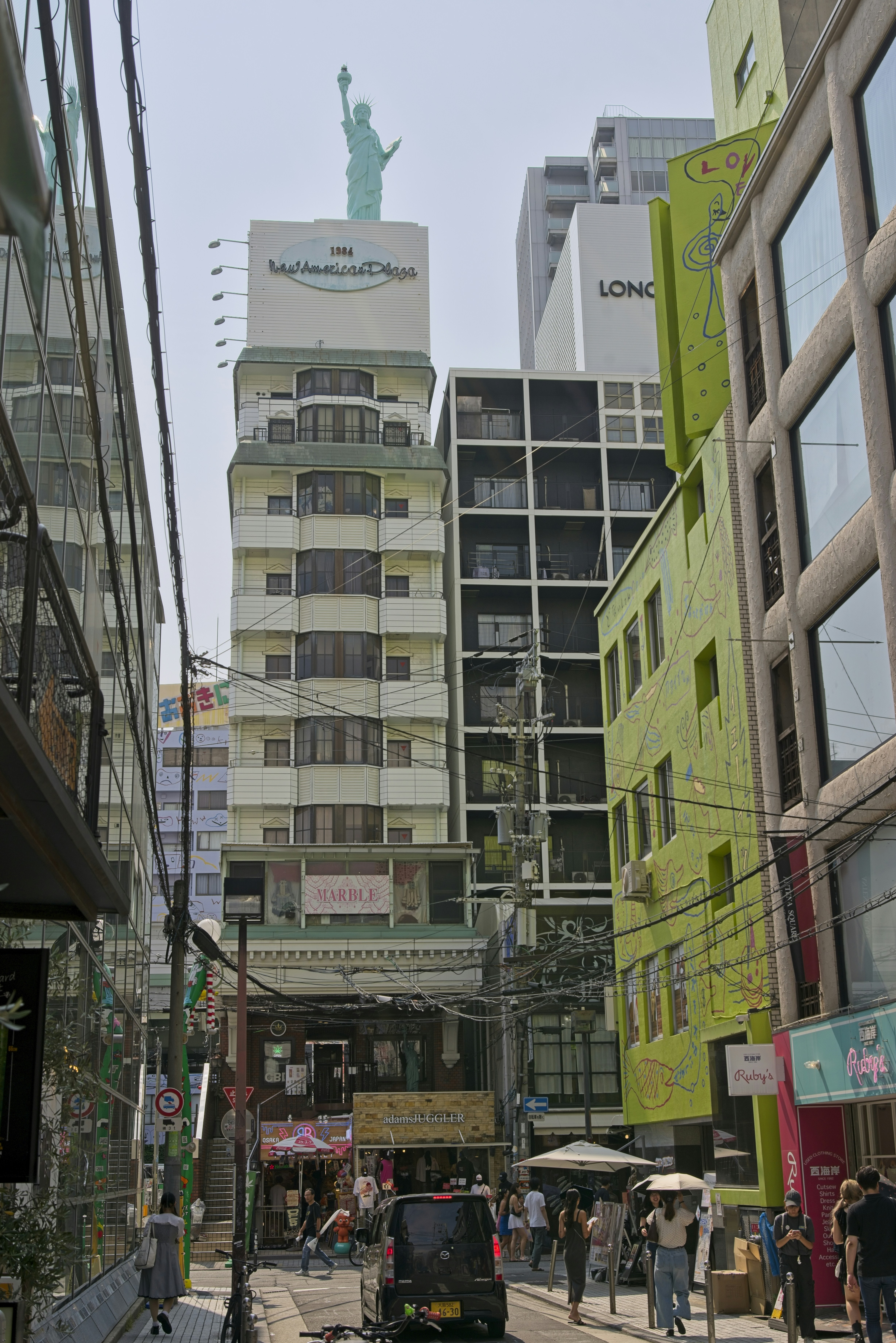 Statue atop a coral-tiered tower lines the neon-clad street