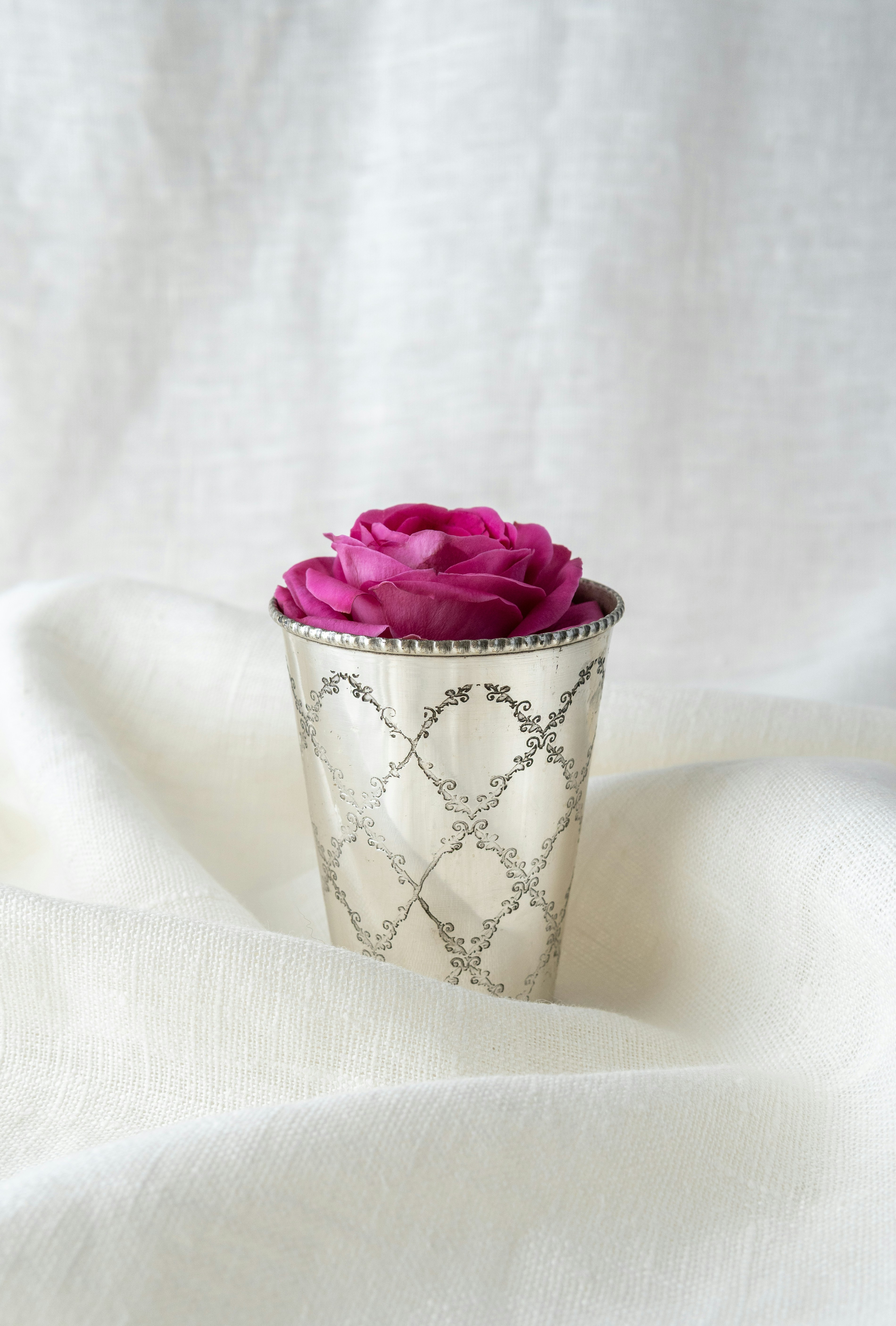 Pink Rose in Ornate Silver Vessel Against Quiet Linen