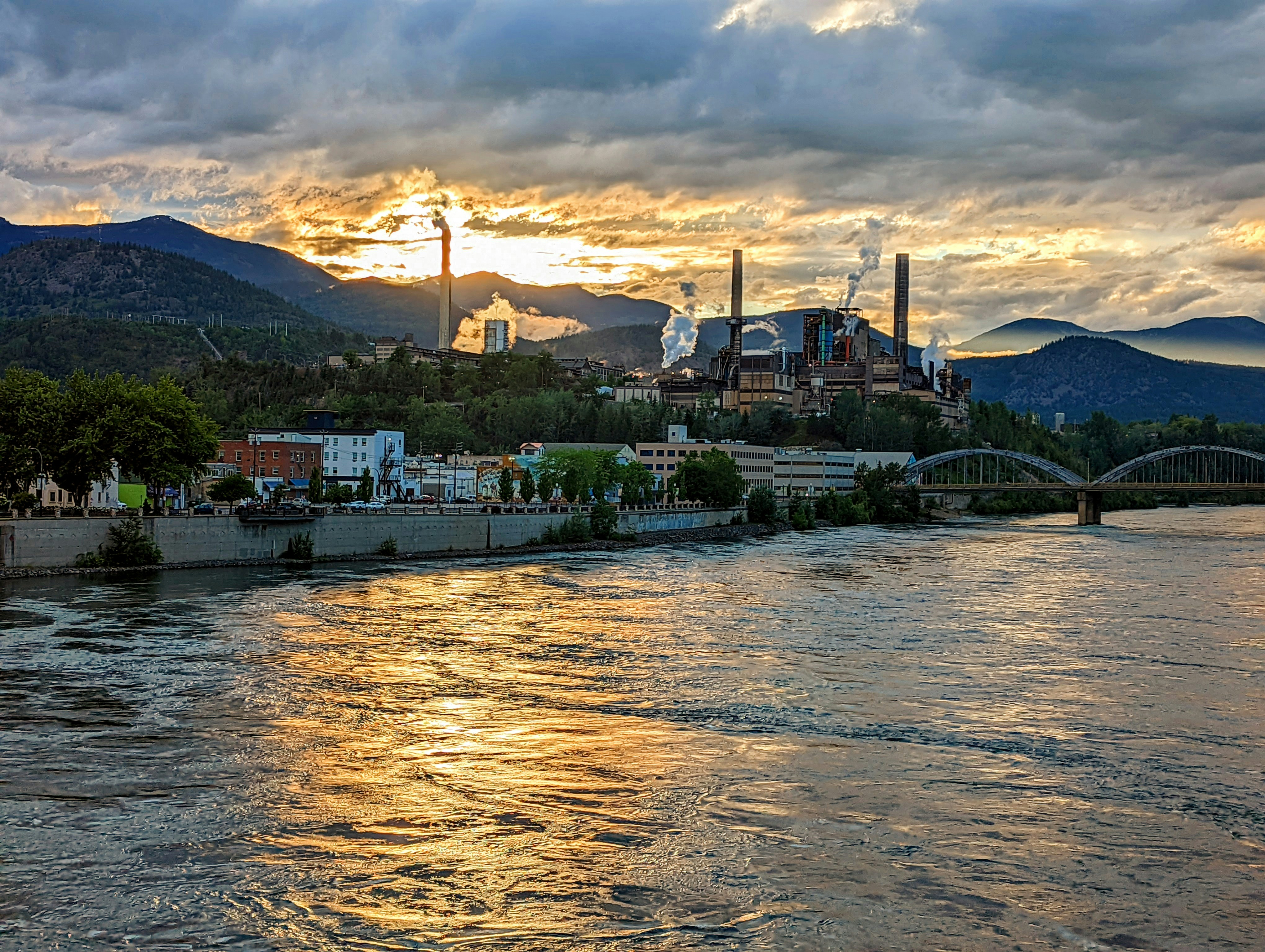 Industrial horizon at sundown: river, bridges, and factory silhouettes