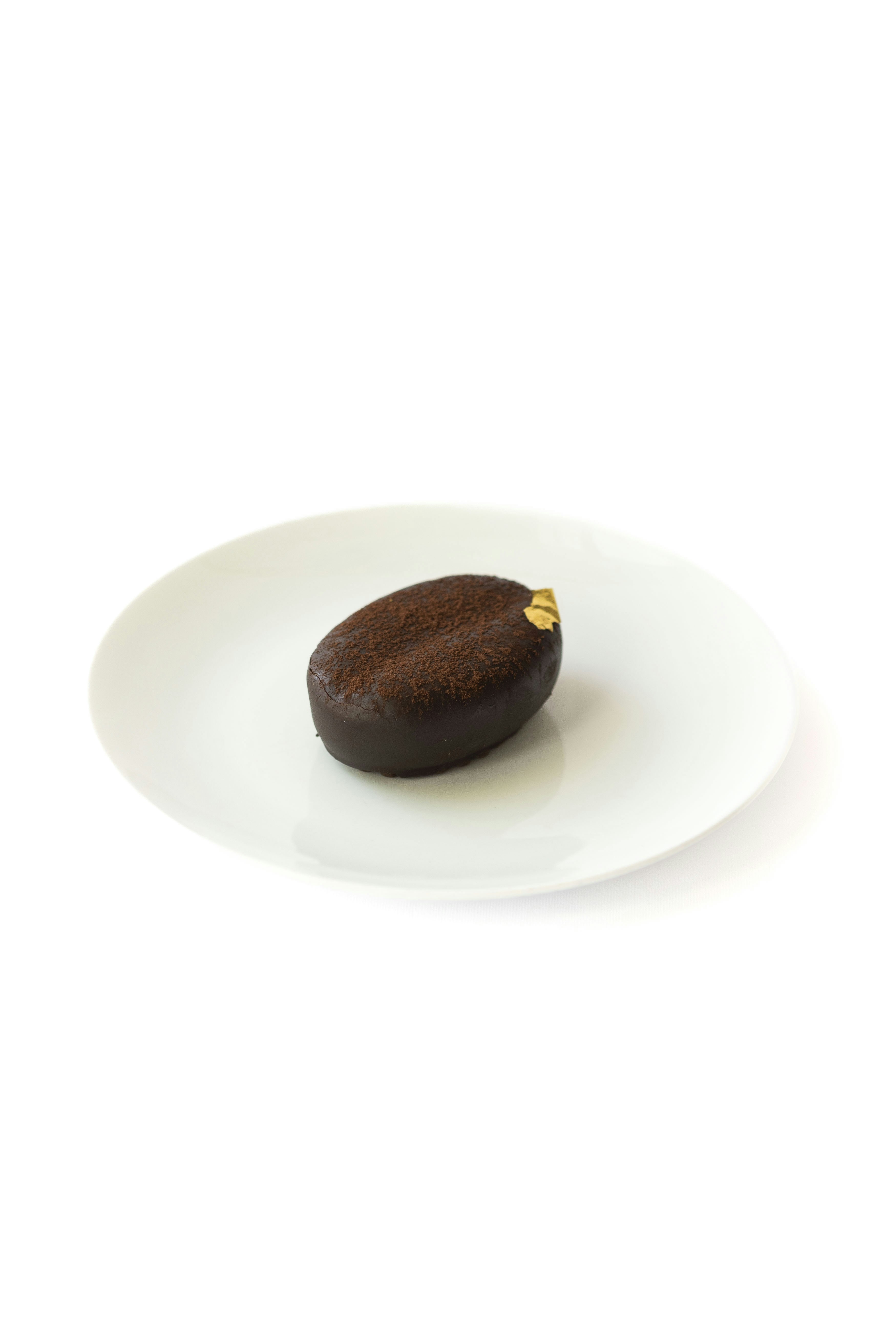 Glossy Chocolate Éclair on a White Plate