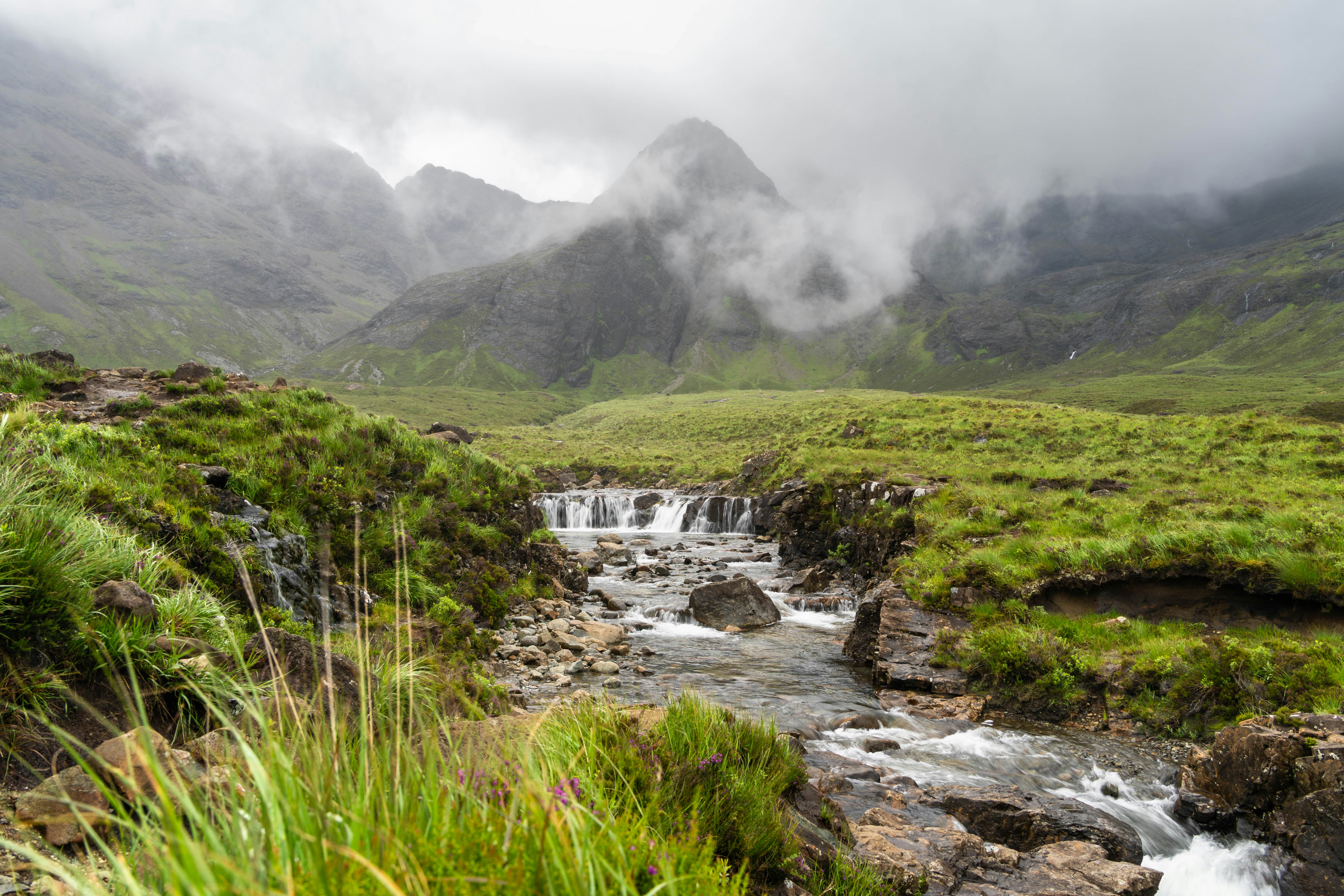 Mossy Stream Cascades Through a Misty Highland Valley