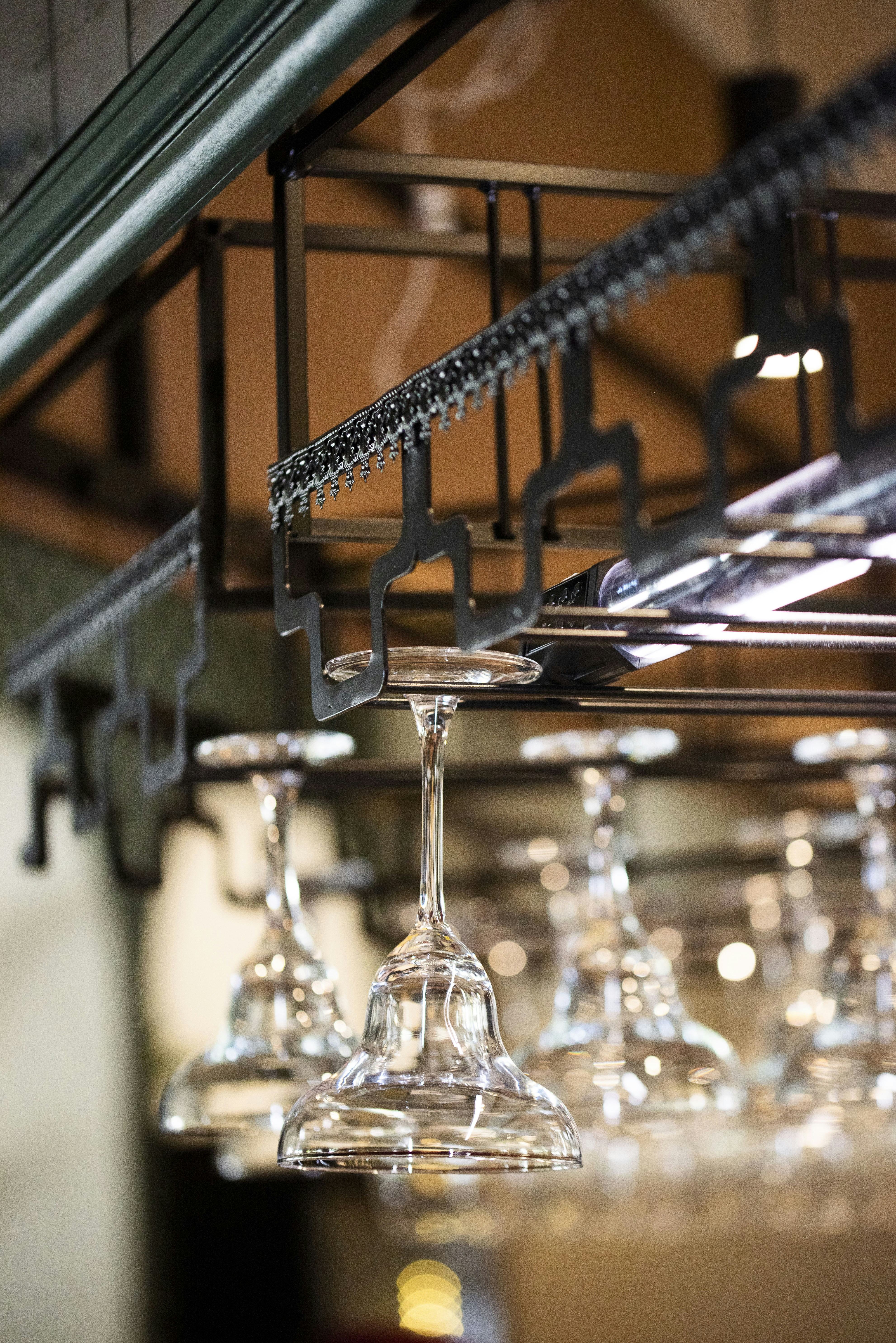 Elevated Glasses: A Row of Wine Glasses Under Overhead Racks