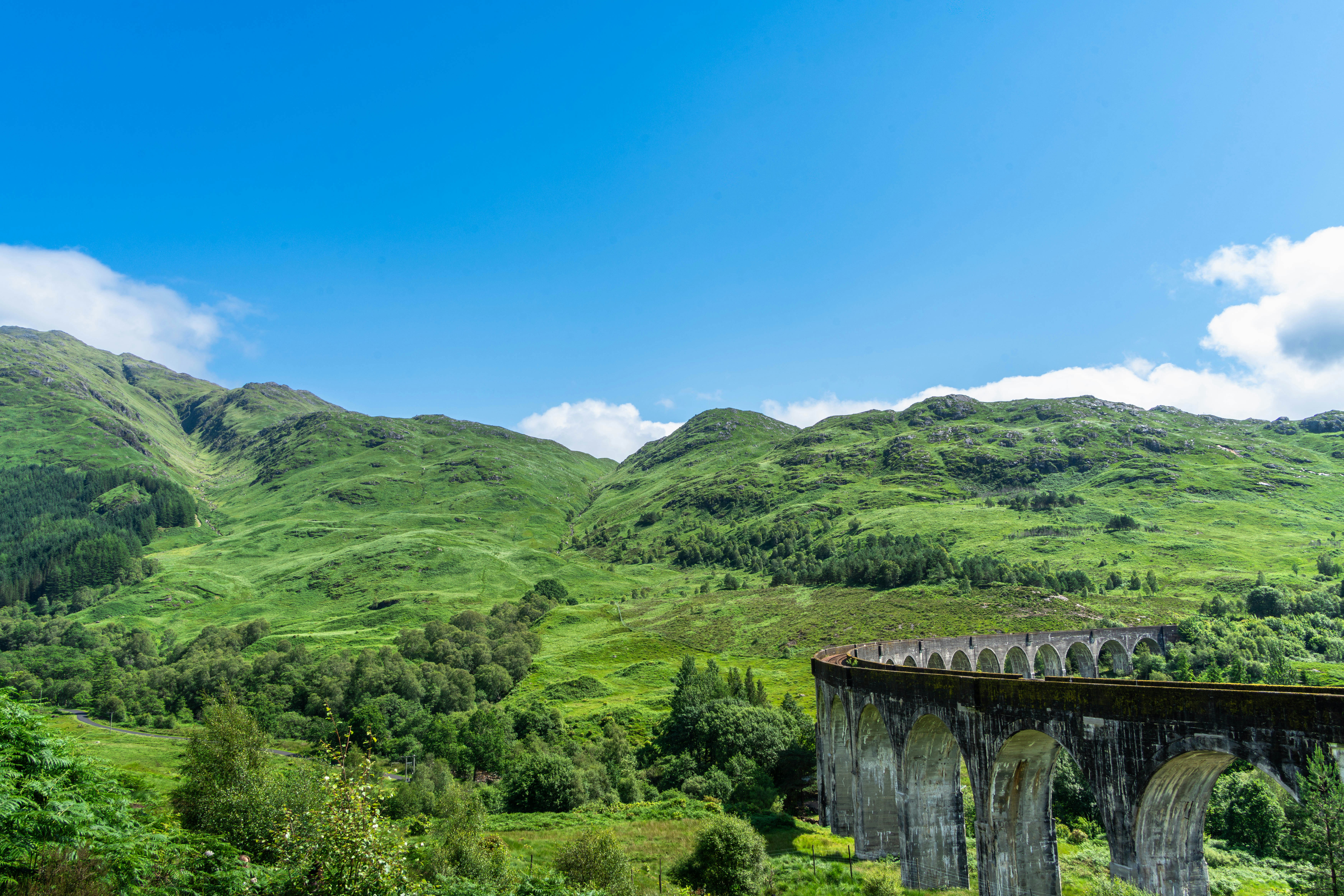 Bridge over rolling green hills under a bright blue sky