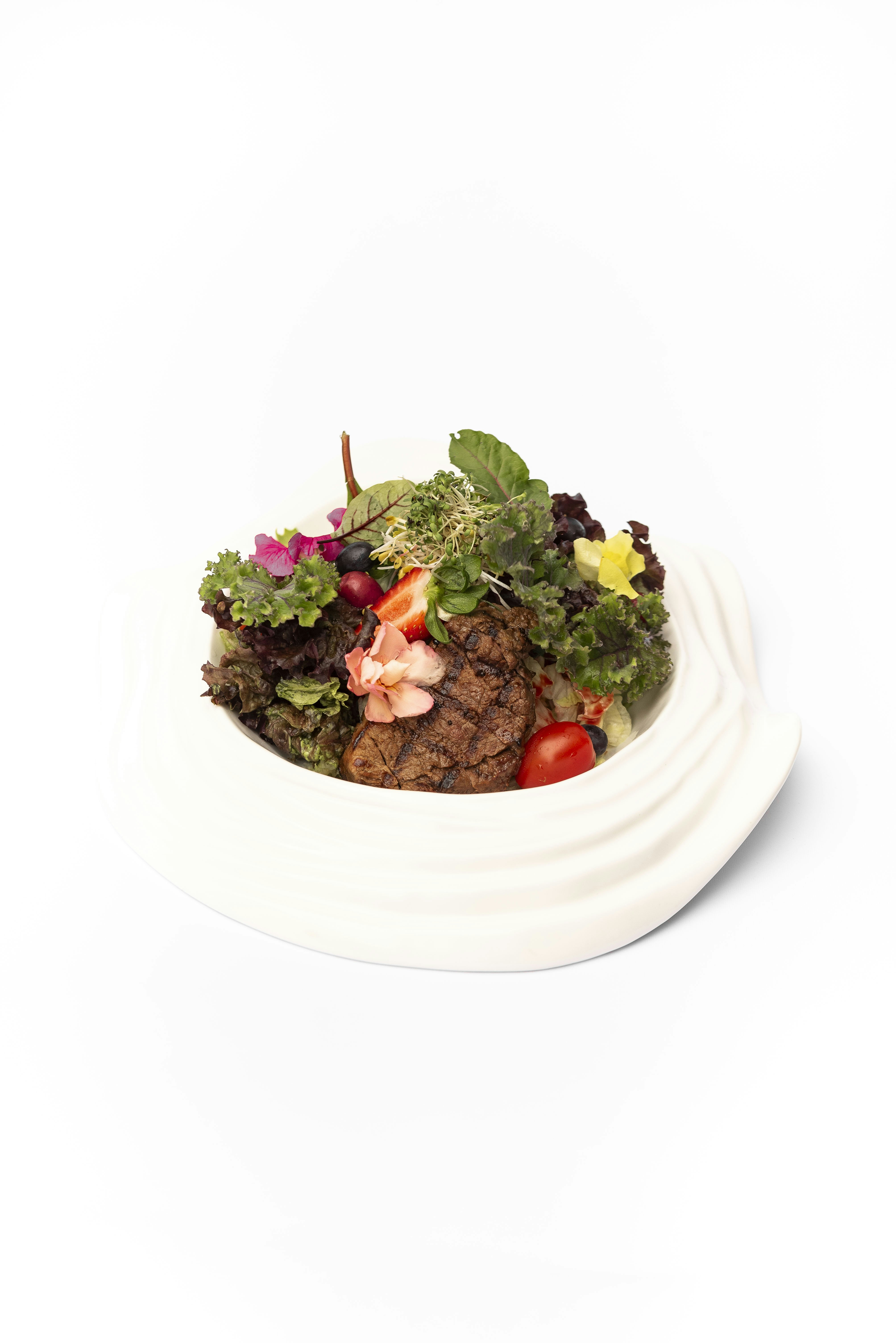 Savory Garden on White: A Modern Plating of Mixed Greens and Roasted Meat