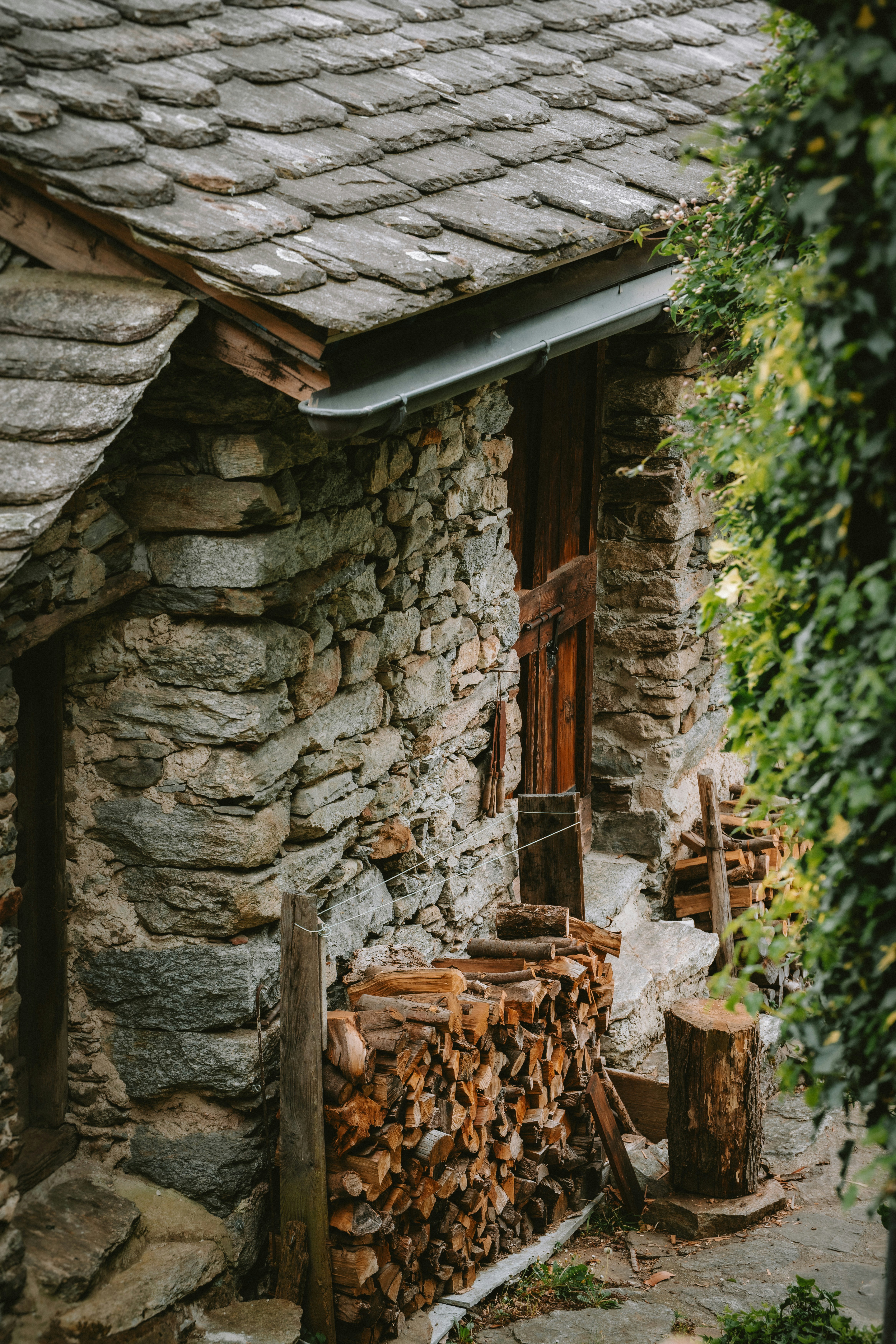Stone cottage with stacked firewood and ivy-clad wall