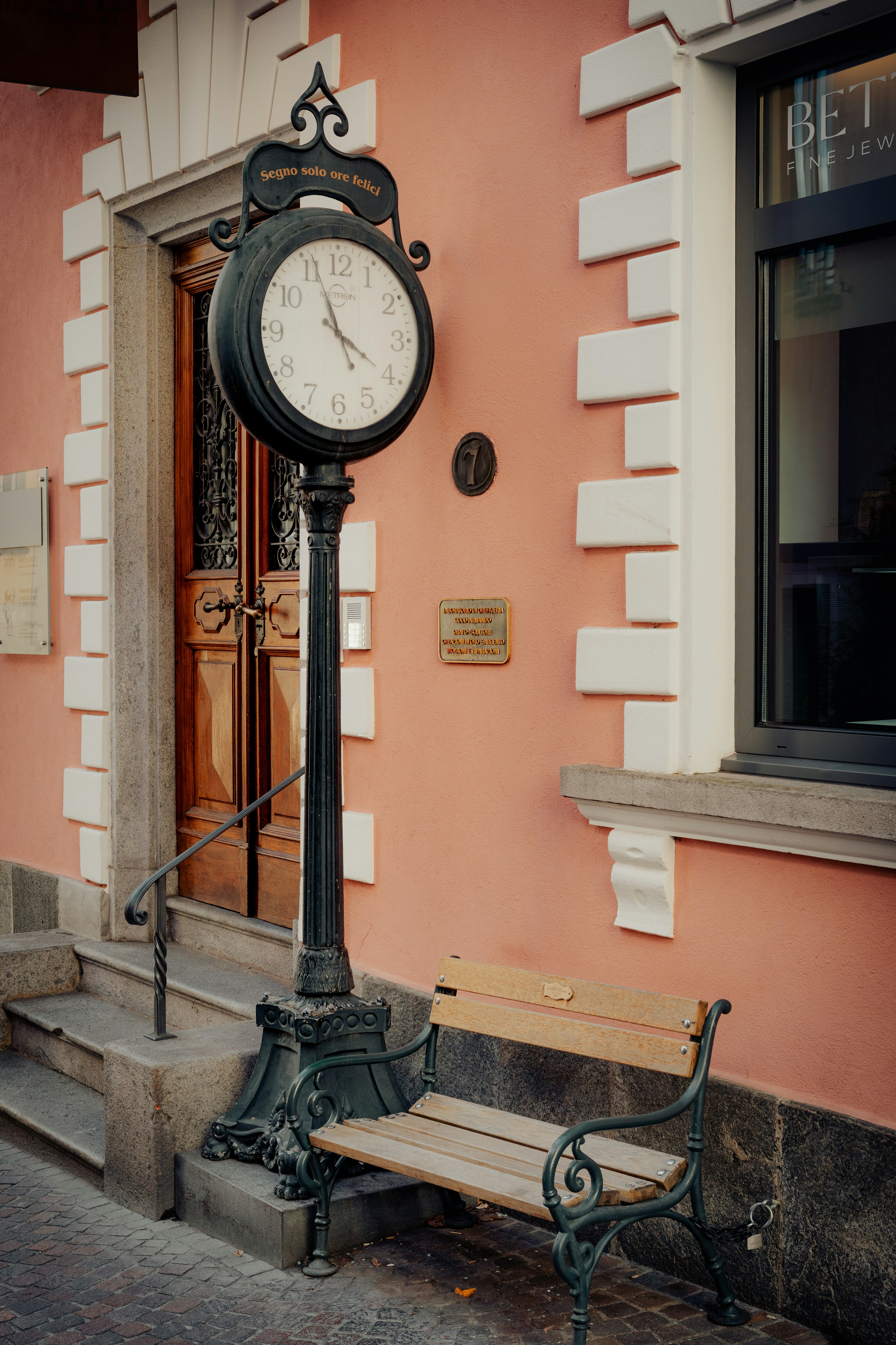 Clock on a Pink Facade: Street Corner with Bench and Old-World Charm