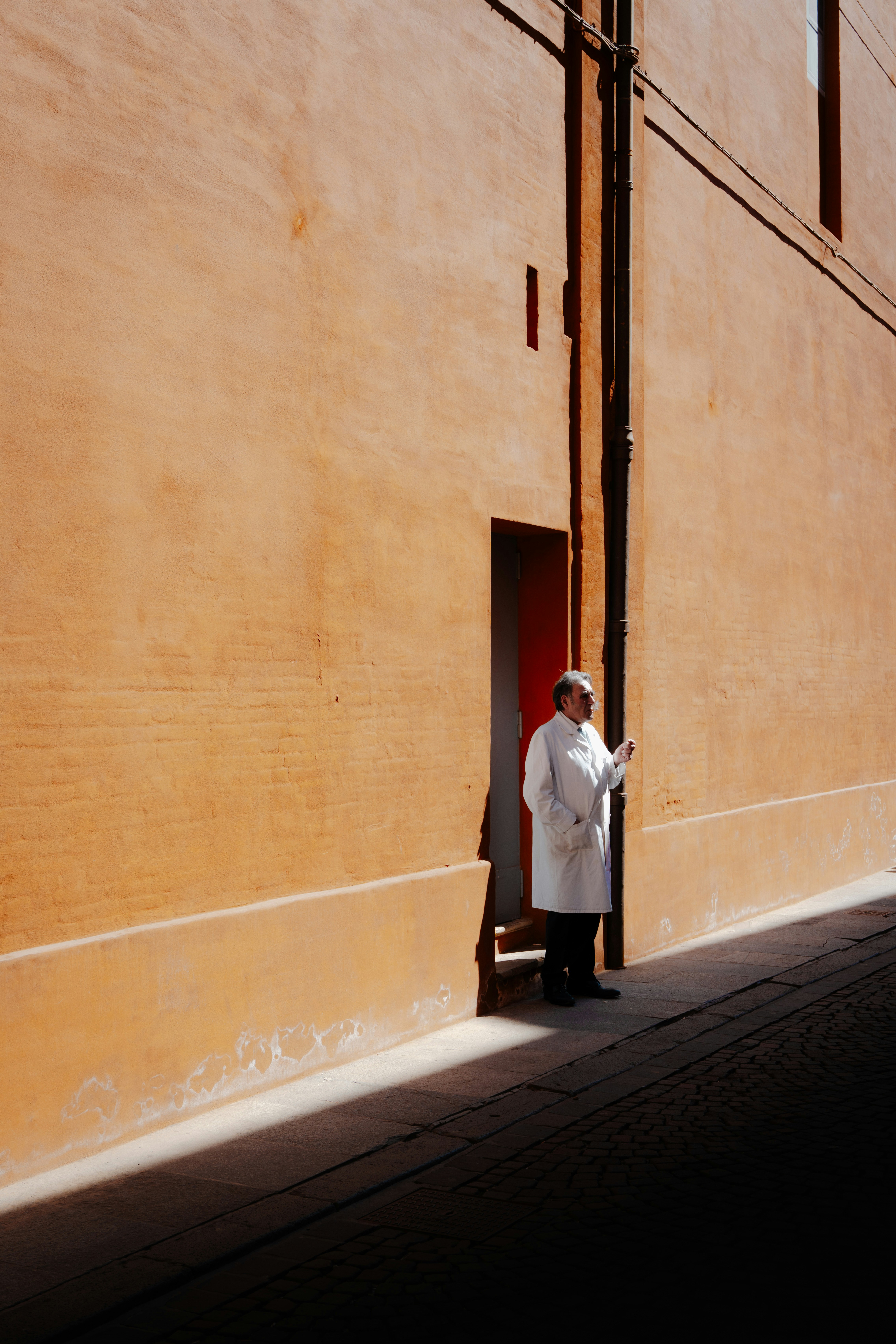 The Doorstep Observer in Sunlit Ochre Facade