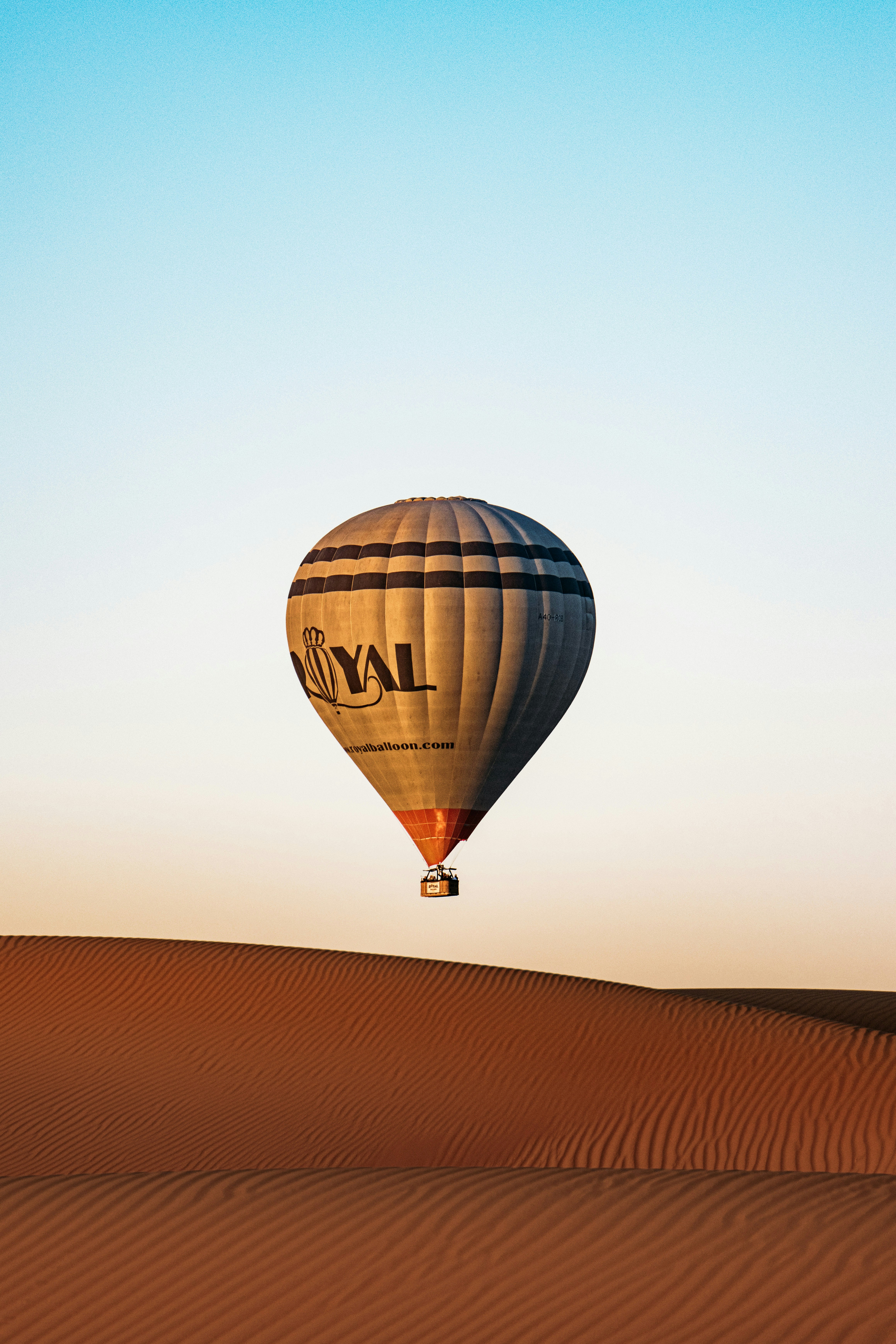 Desert Lift: A Balloon Soars Above Dune Waves at Sunset