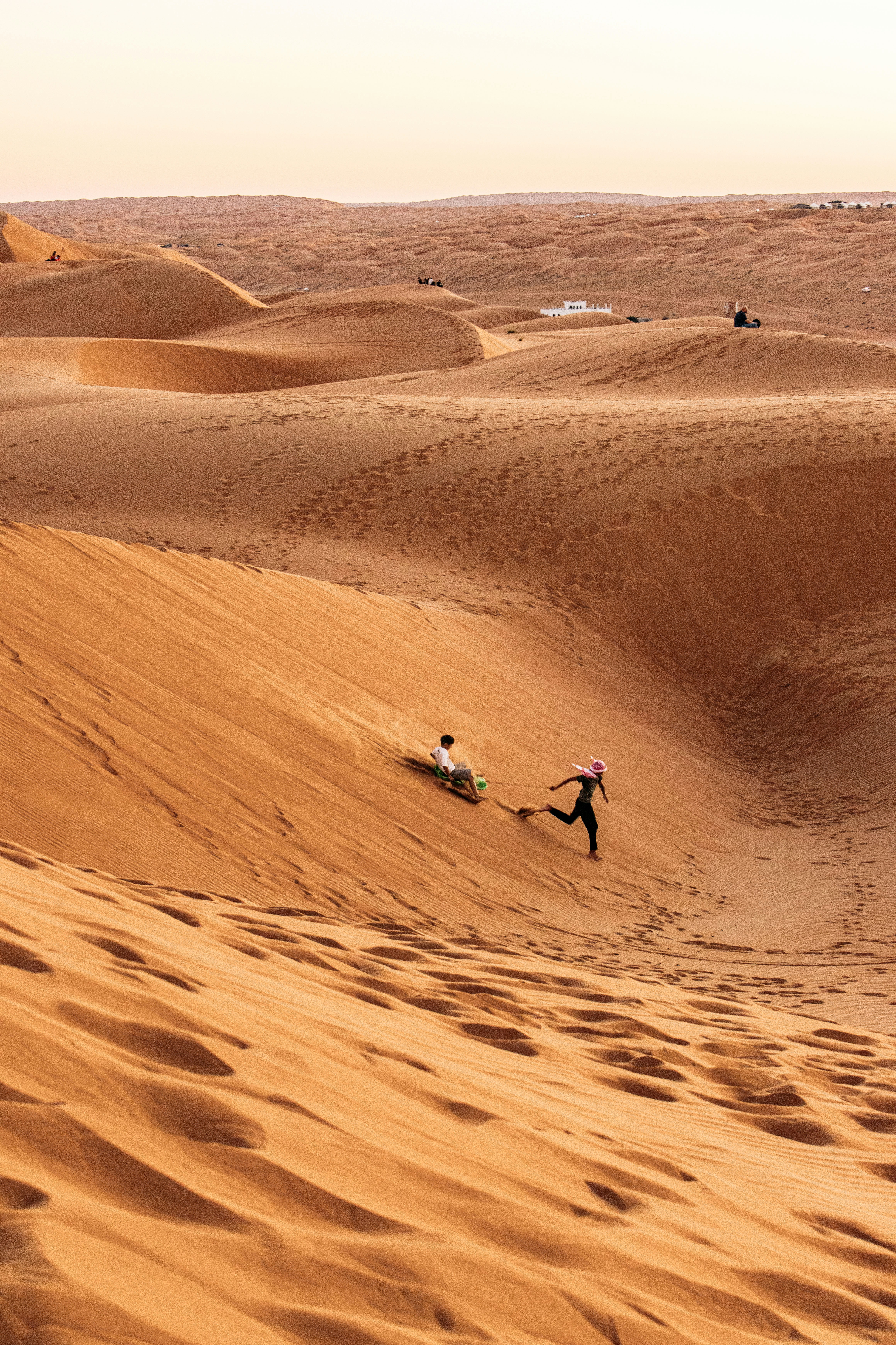 Desert Dunes: A Pair of Climbers Carving Paths Across Amber Seas