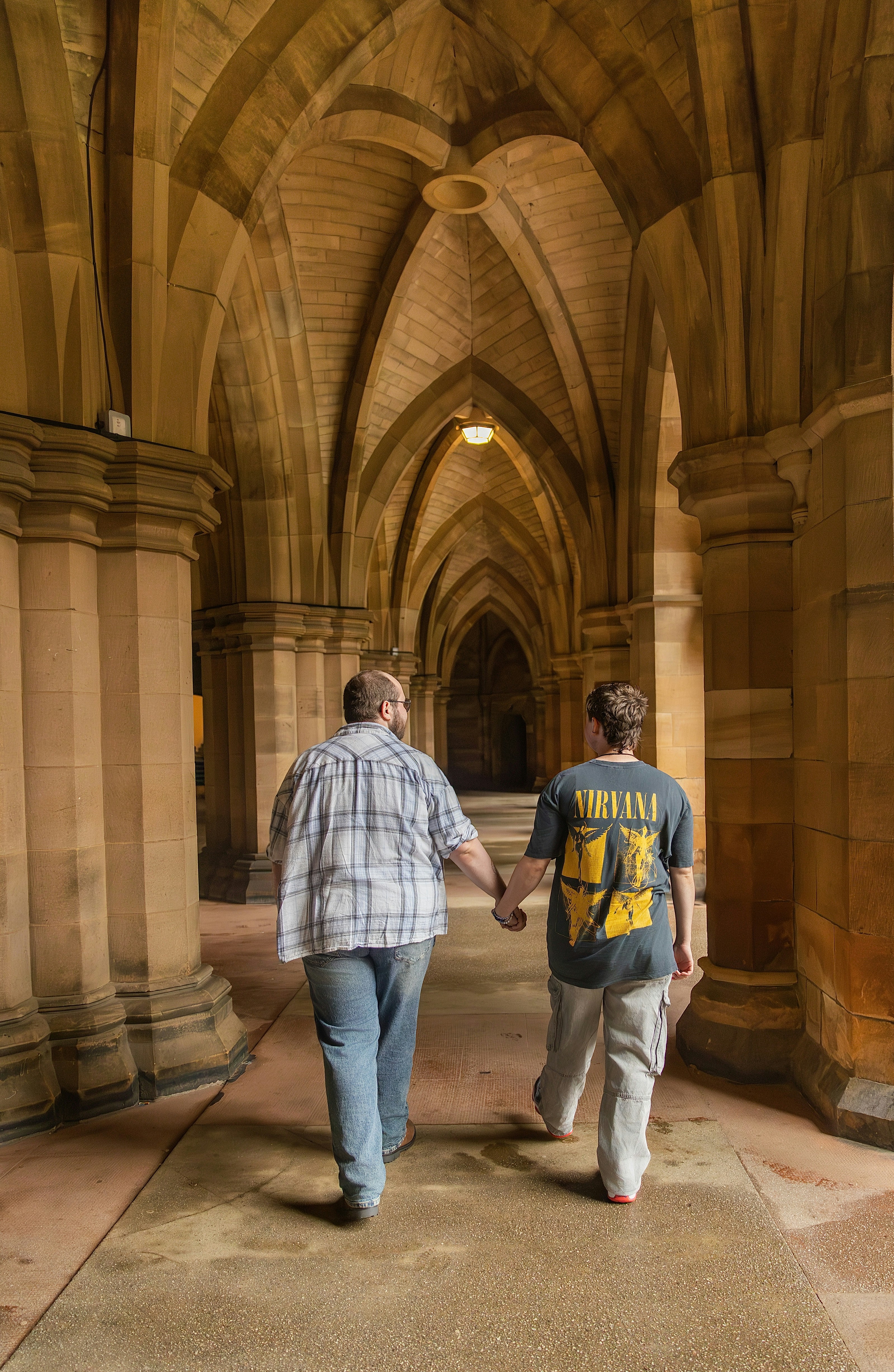 Two Friends Hand in Hand Through a Cathedral Corridor