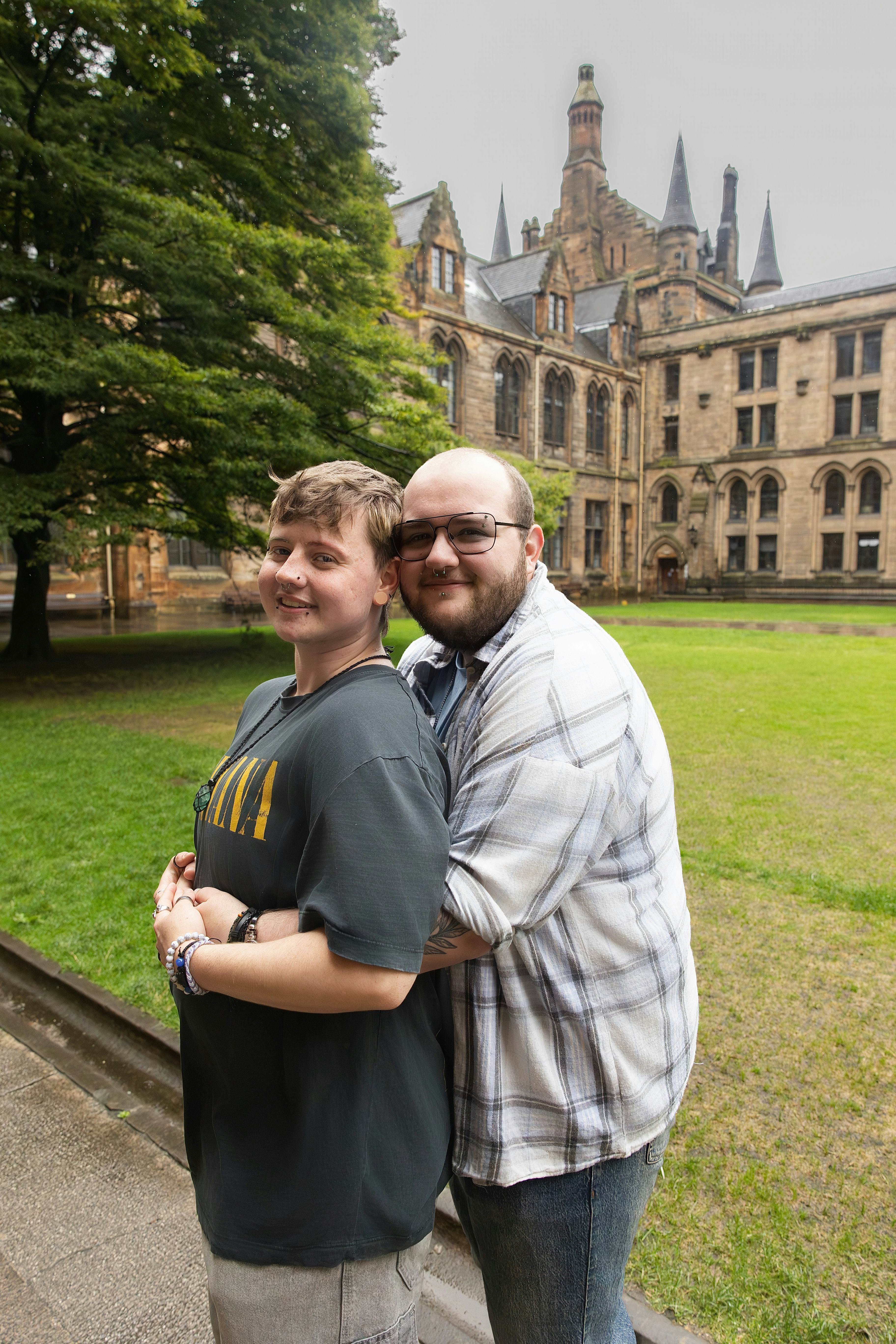 Two adults embracing in front of the historic University of Glasgow main building
