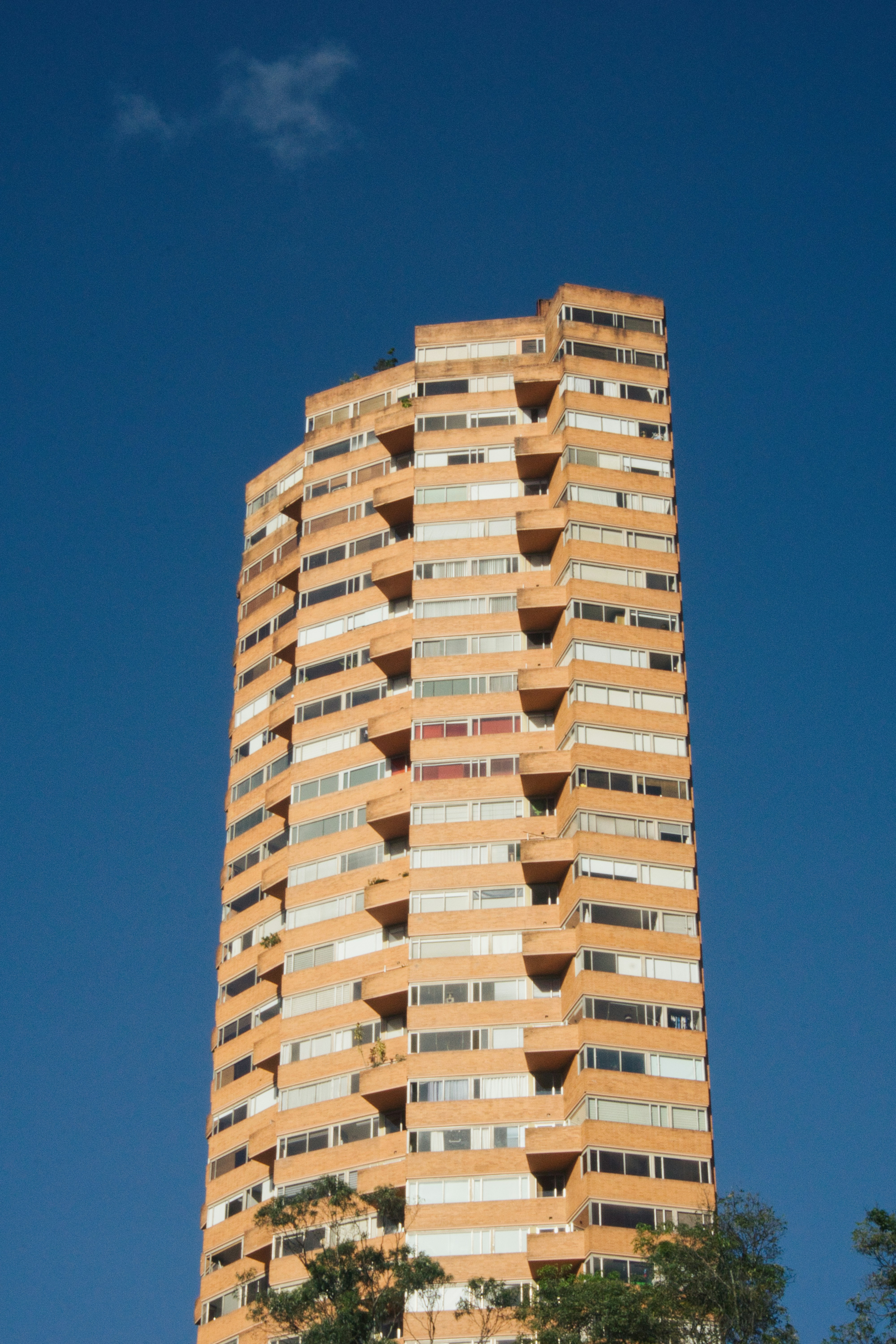 Skyward Colonnade: A Brick-Orange Tower Reaching the Clear Morning Sky