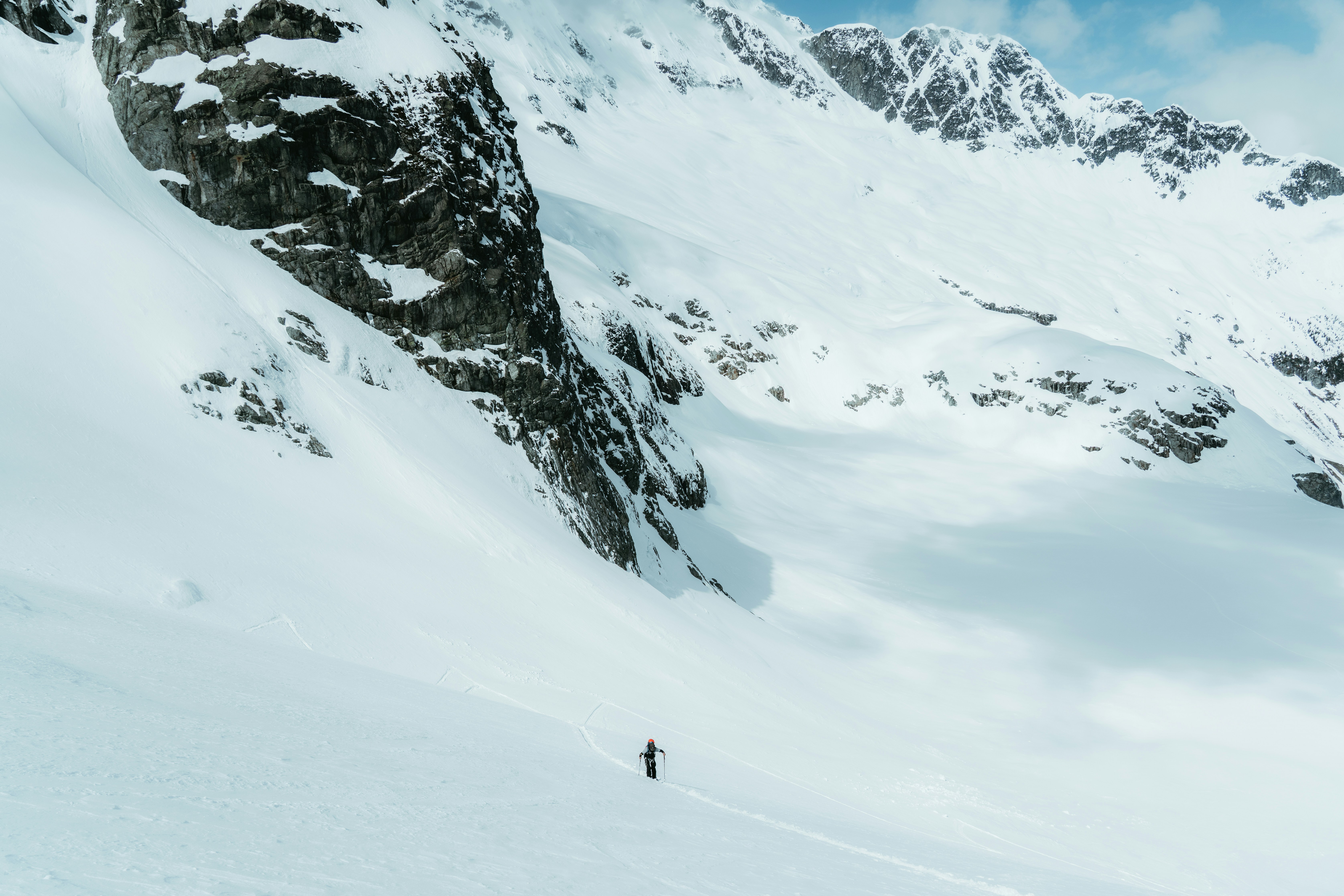  lone climber carved through a vast glacier bowl beneath towering ice and rock