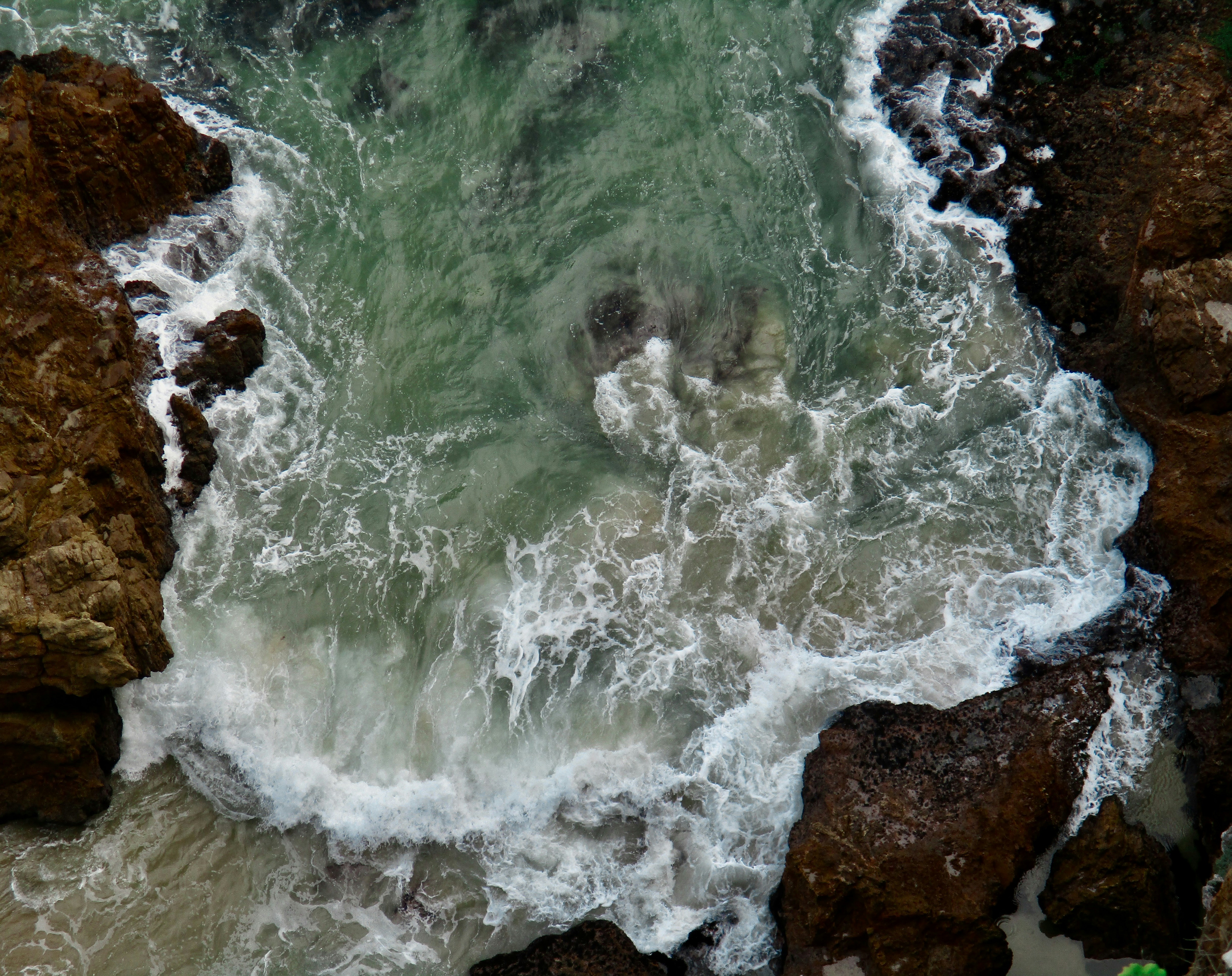 Rugged coastline churn: turquoise surf meeting basalt cliffs from above