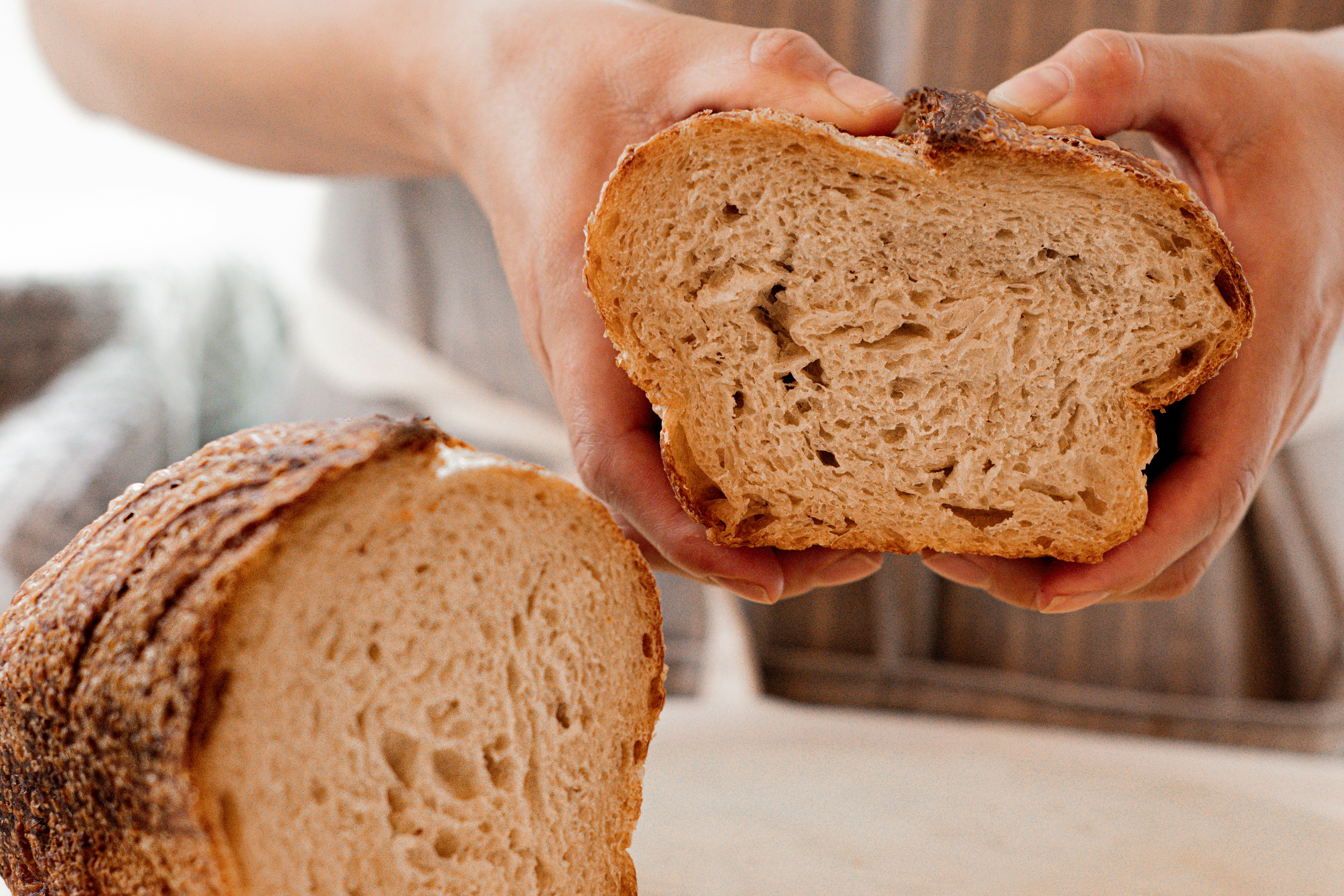 Sliced loaf held mid-air, crumbly interior revealing yeast-risen texture