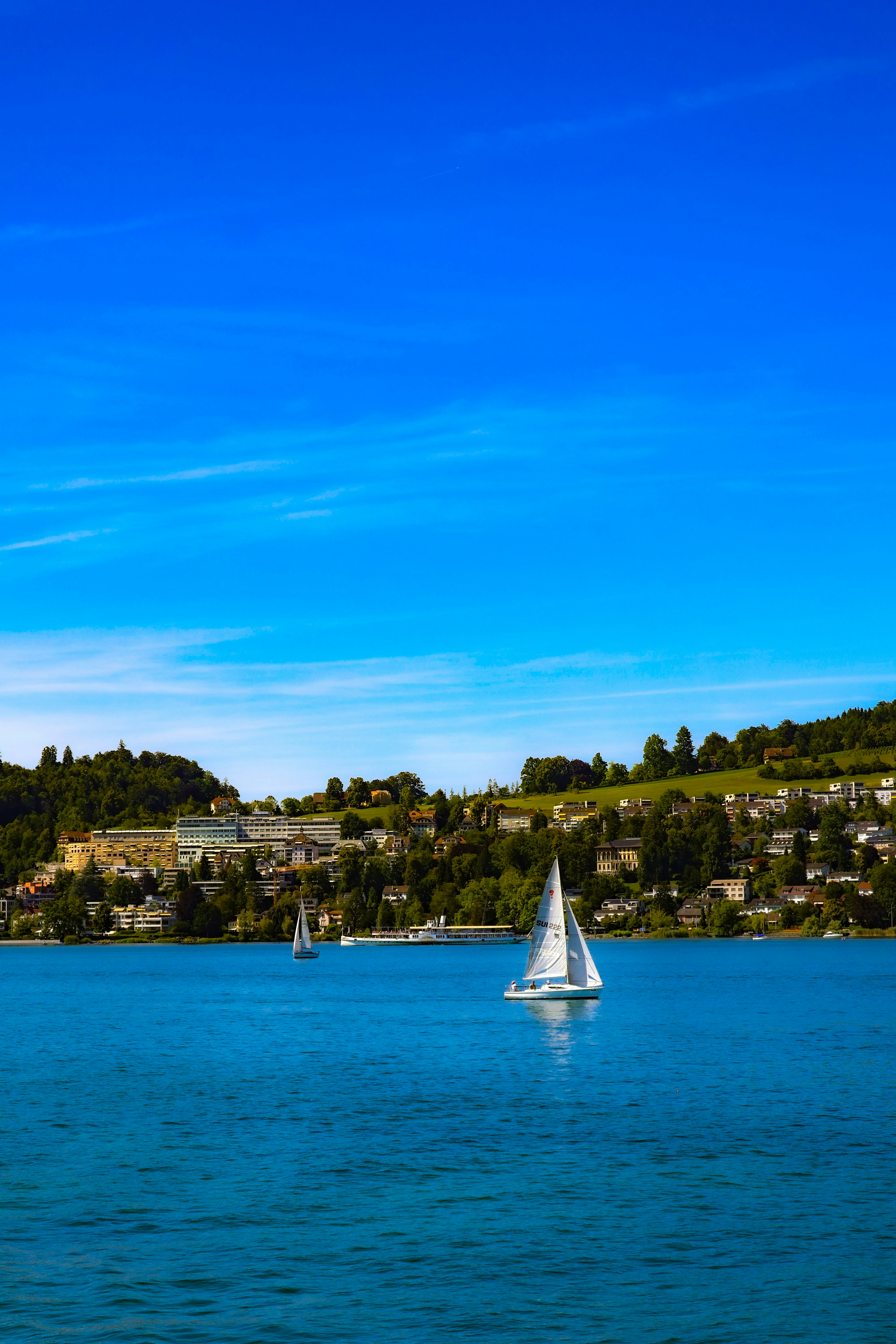 Sailboats on a Glinting Lake Beneath a Wide Blue Sky