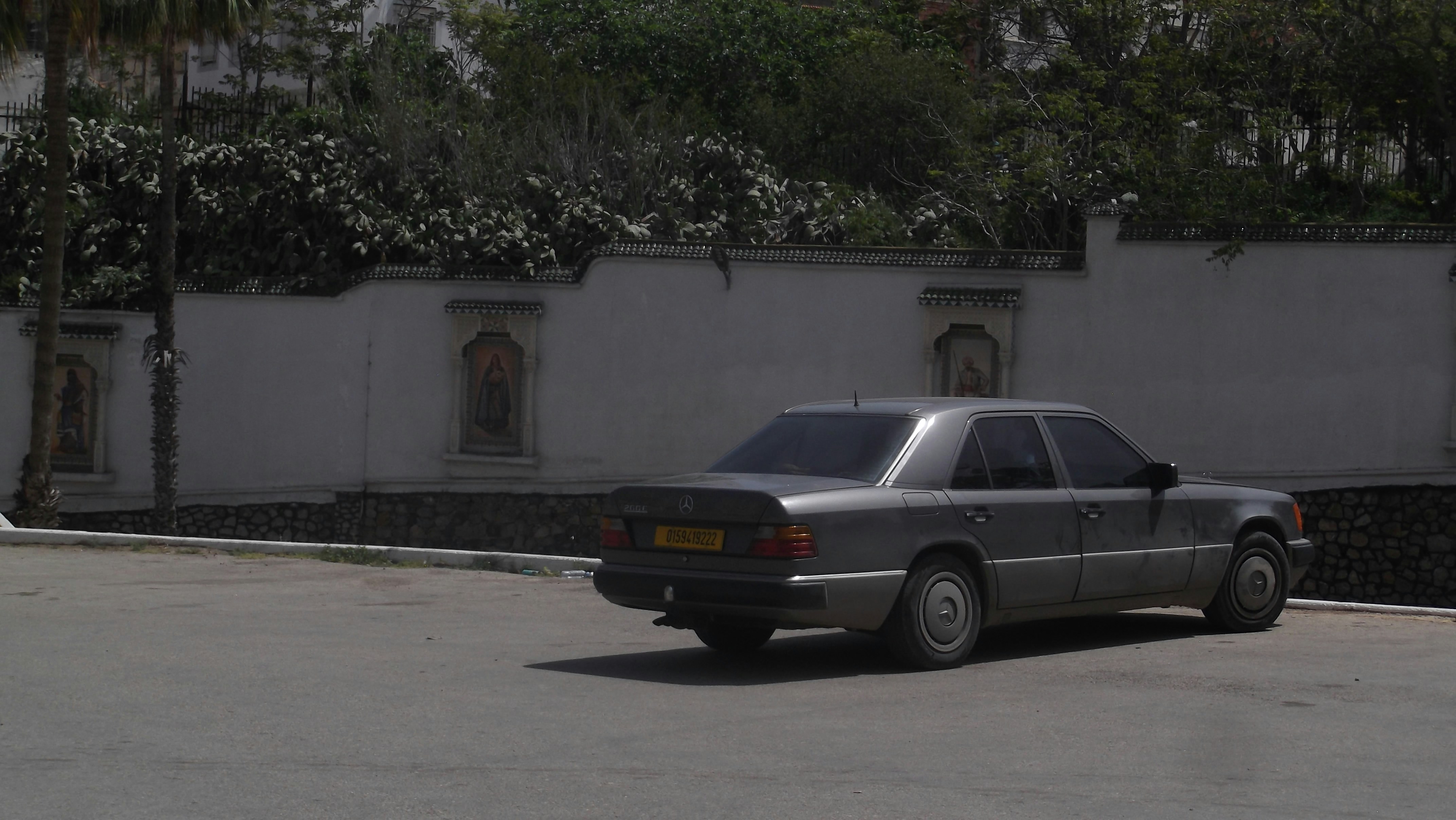 Midday ride: a vintage sedan loafing beside a quiet courtyard wall