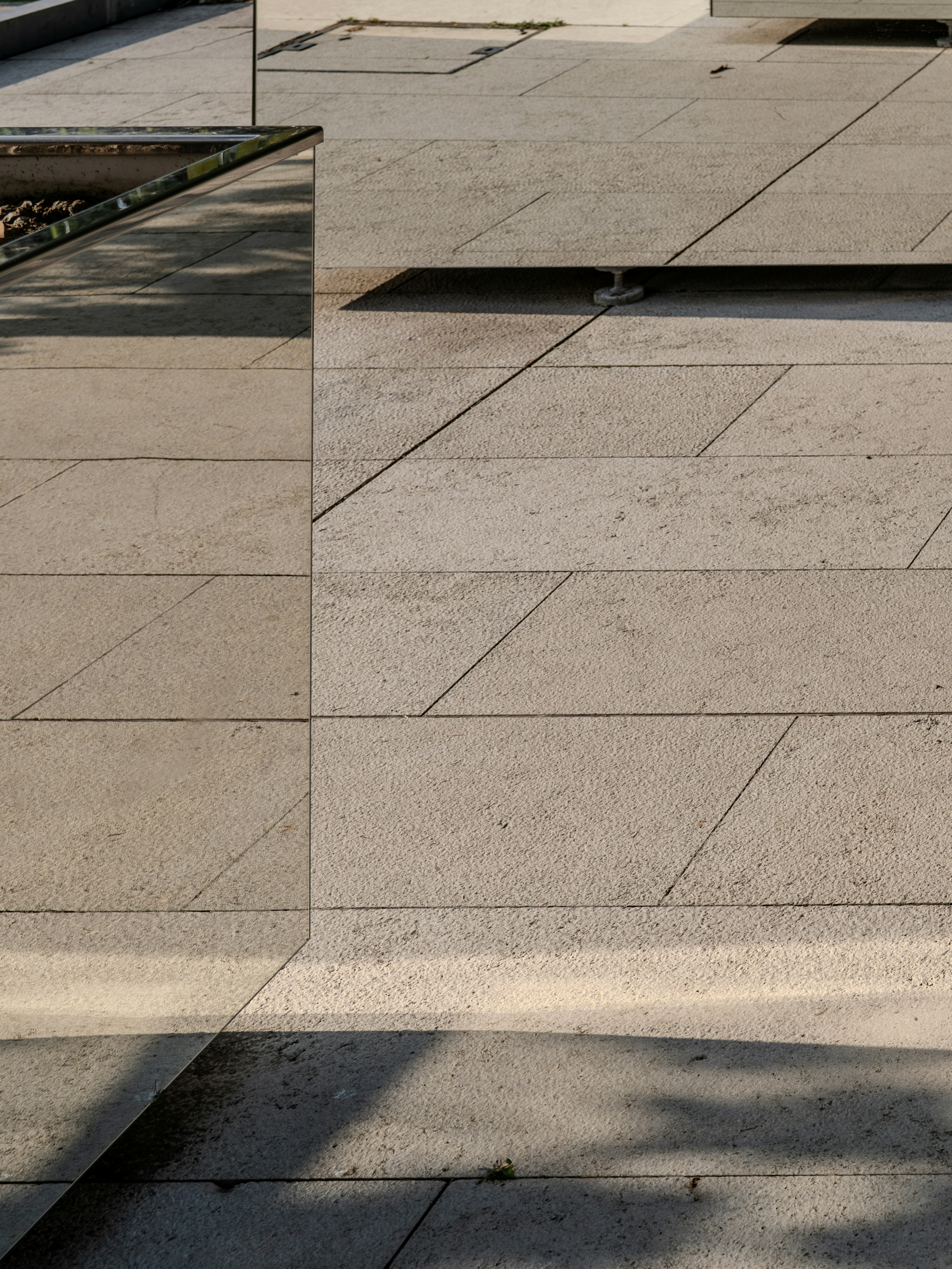 Glass-edged balcony and diagonal shadows over a sunlit plaza