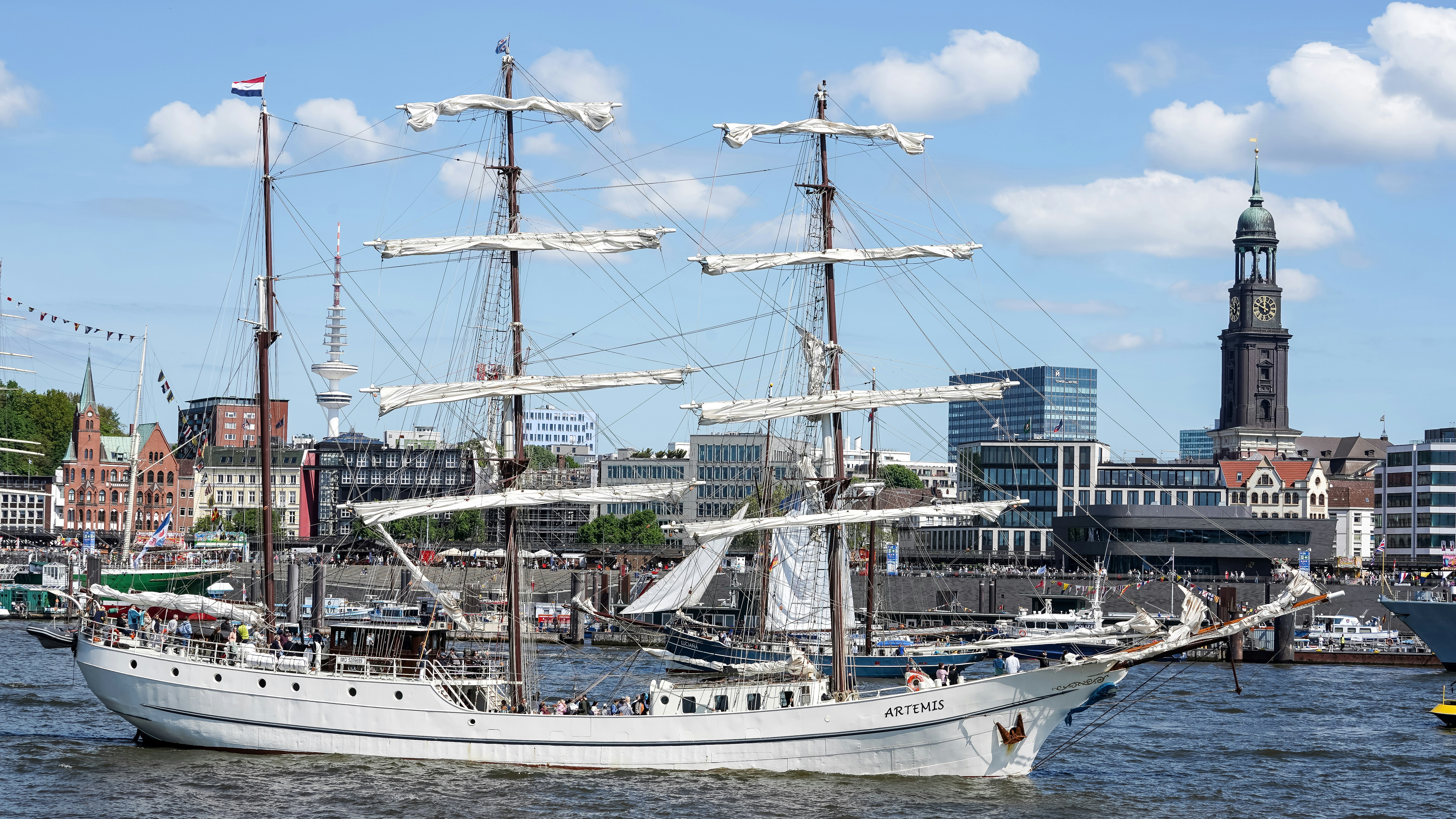A Majestic Tall Ship Anchored by a City Harbor