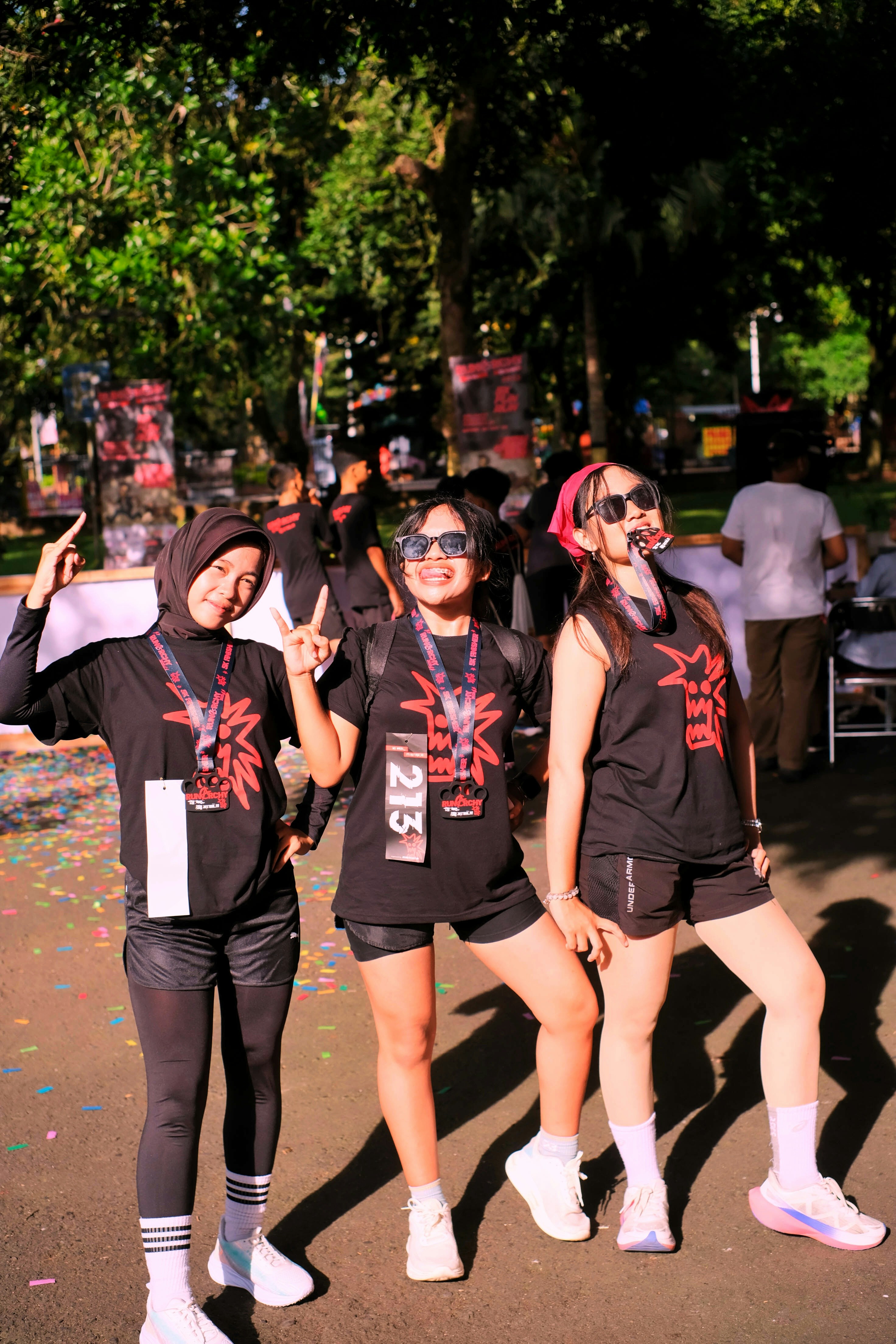 Three carefree performers strike victory poses at a festive outdoor event