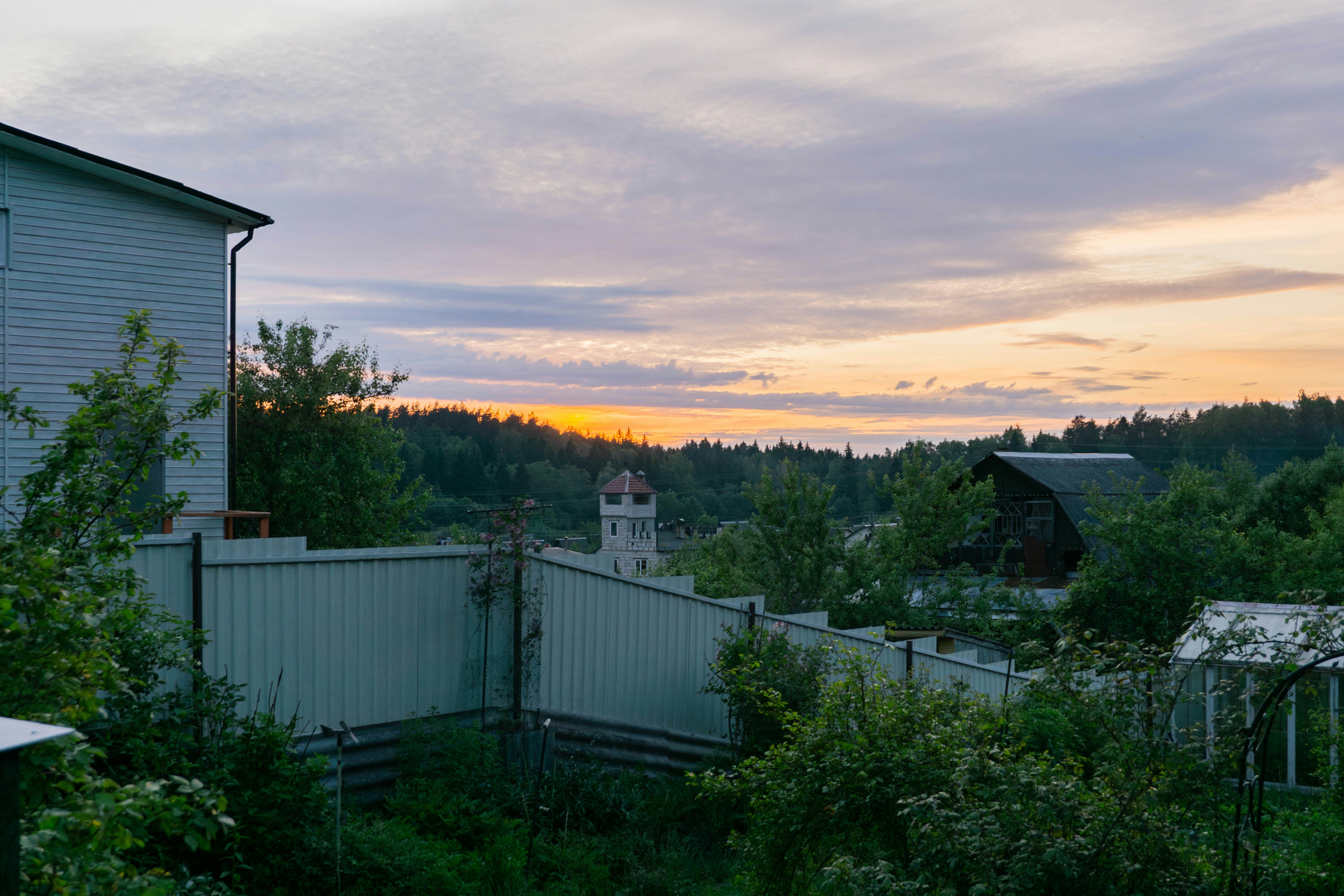 Dusk over the Quiet Suburbs: Rooftops, Fence Lines and a Distant Clock Tower