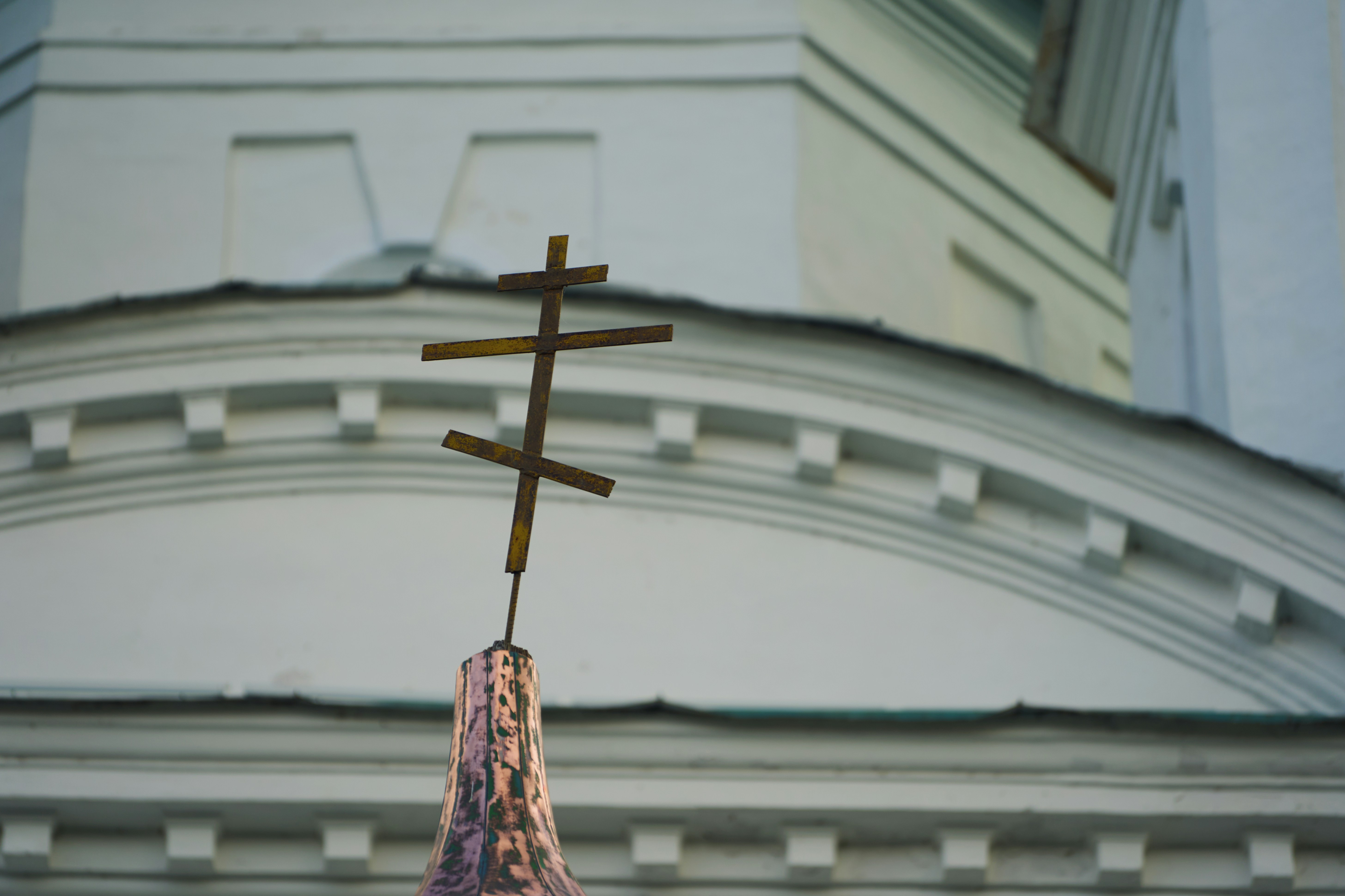 Triple Cross on a Weathered Spire Against a Classical Facade