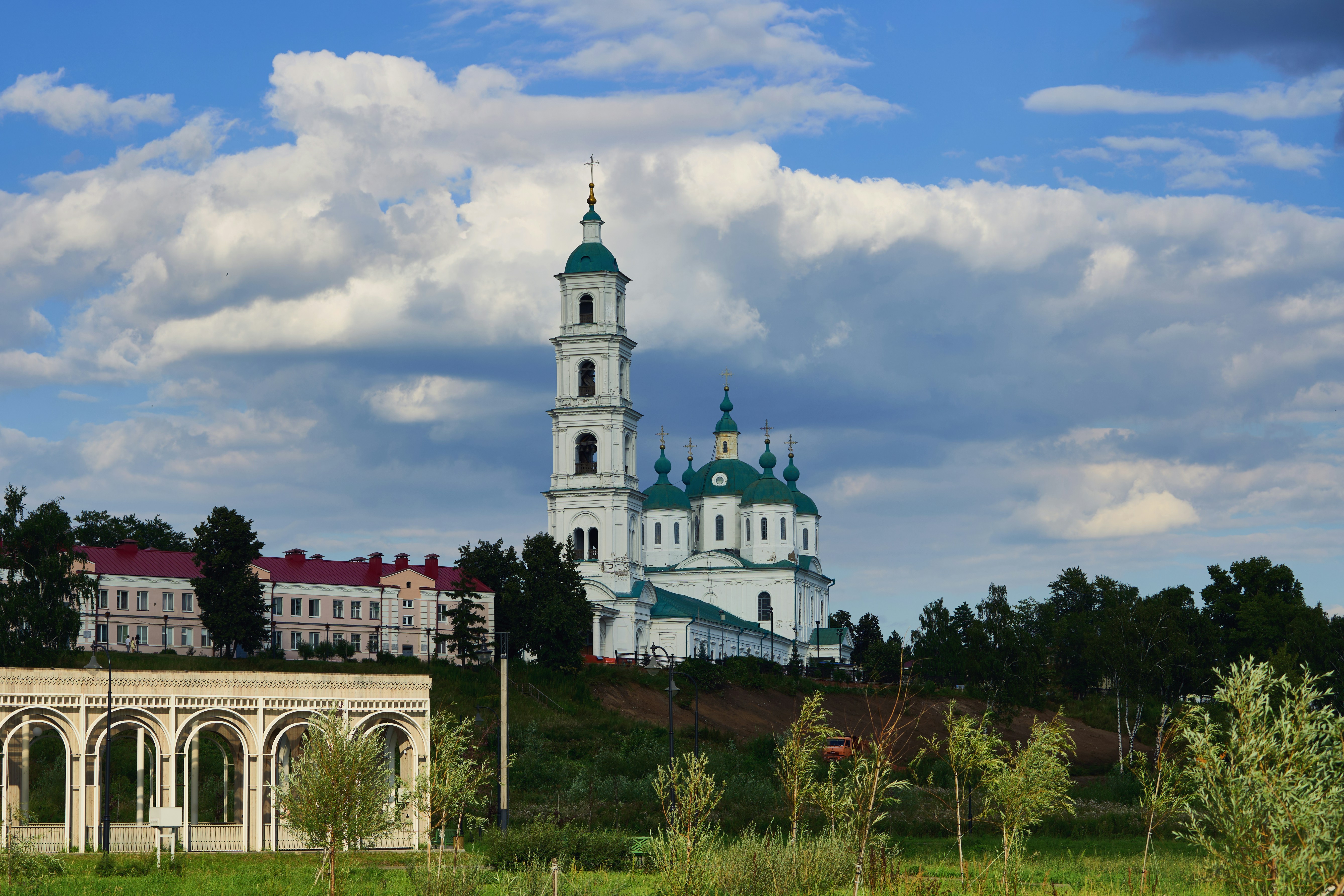 Tiered Happiness: A Riverside Orthodox Cathedral Rising Over Greenid Fields