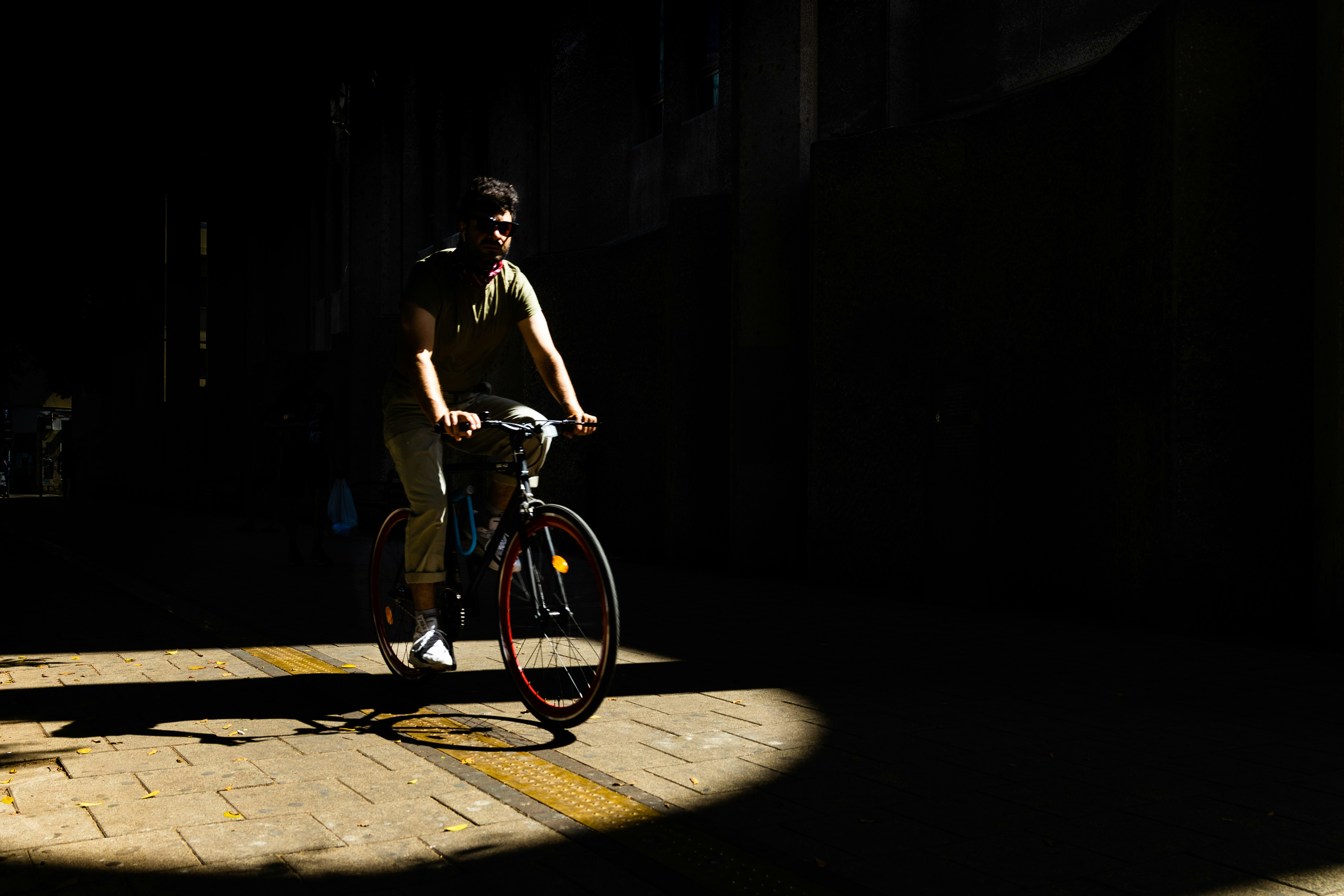 Spotlight Rider: A Lone Cyclist Emerging from Shadow
