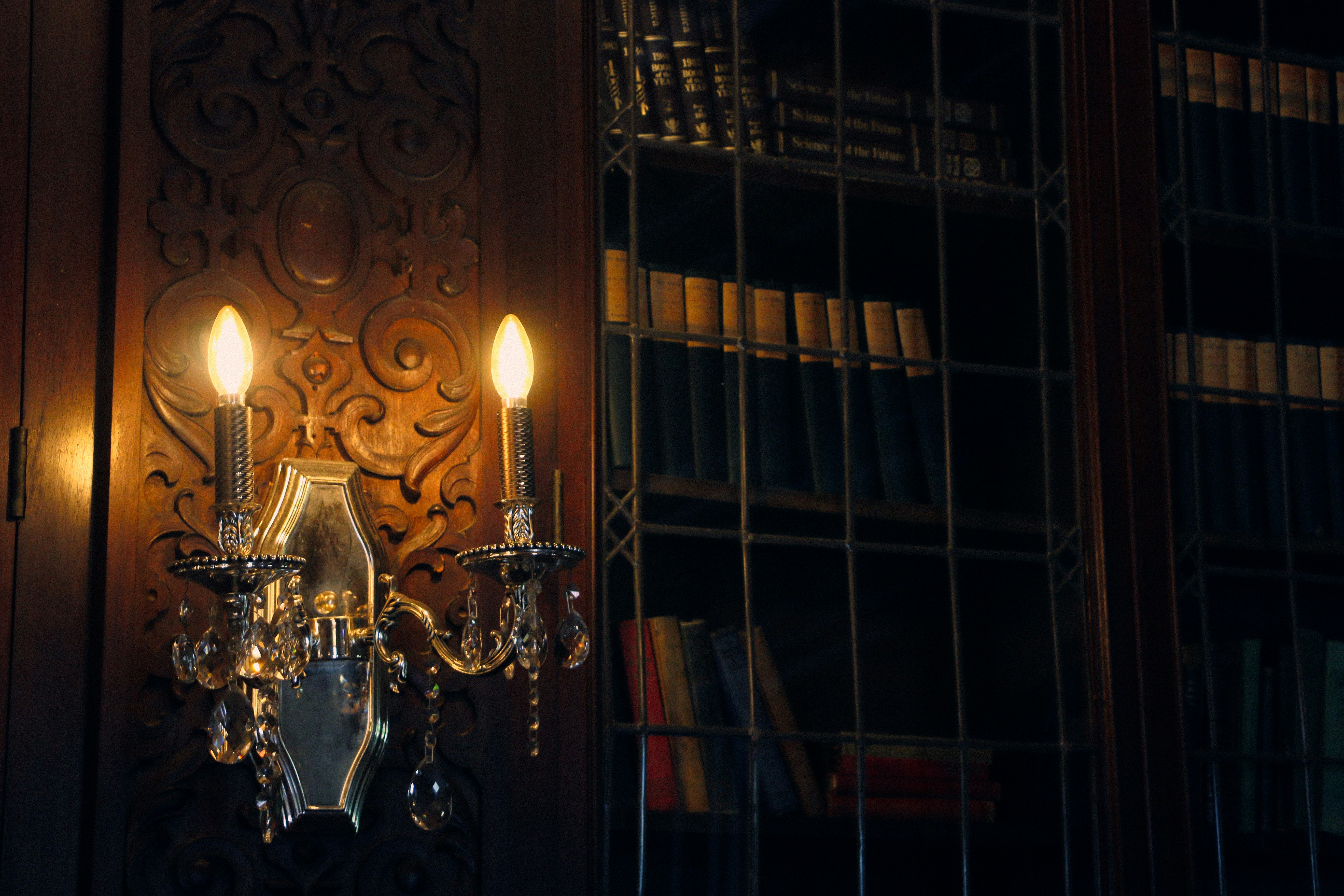 Candlelit Library: Crystal Chandeliers against Ornate Carved Wood