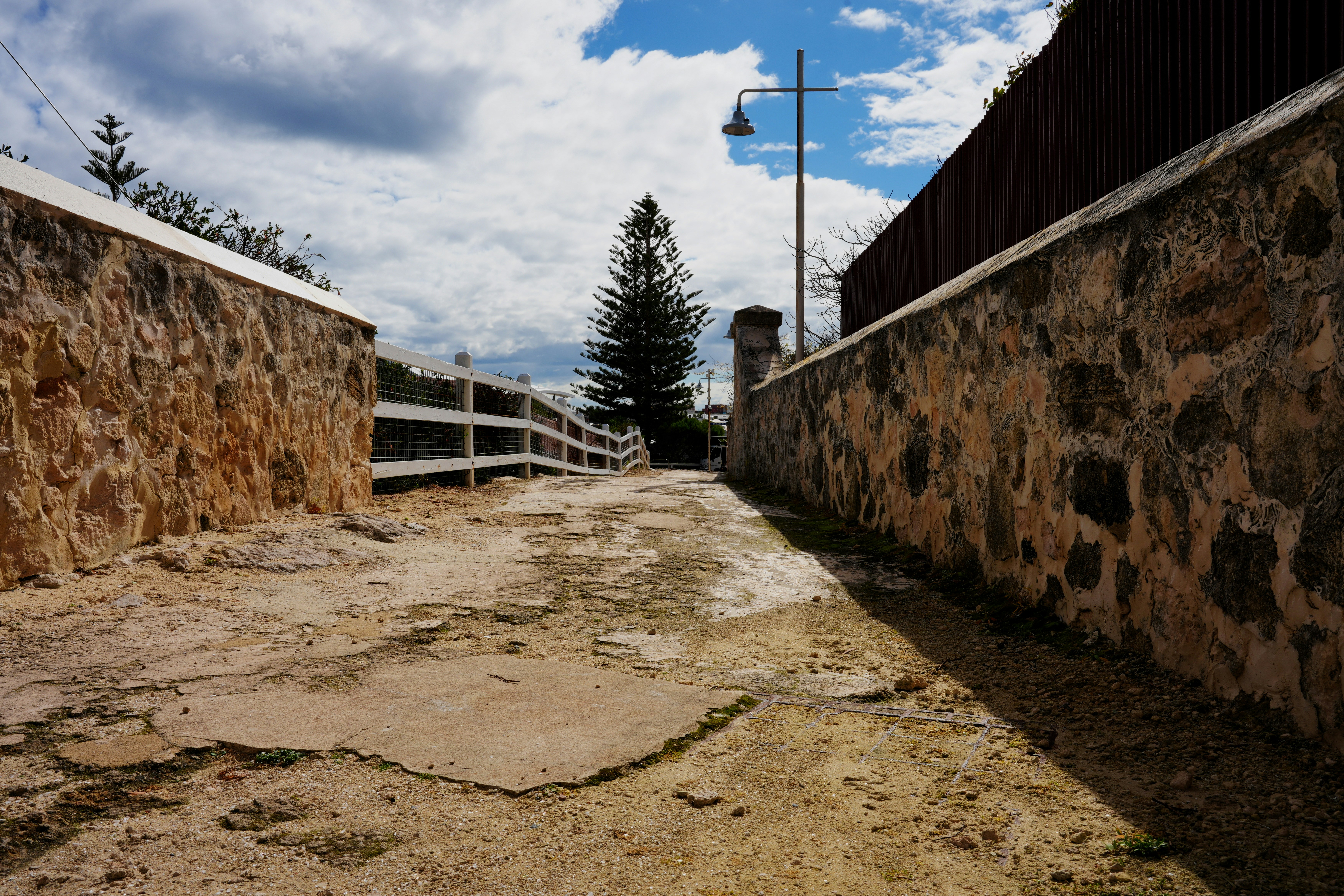 Rugged Pathway Between Sturdy Stone Walls Under a Sky of Light and Shadow