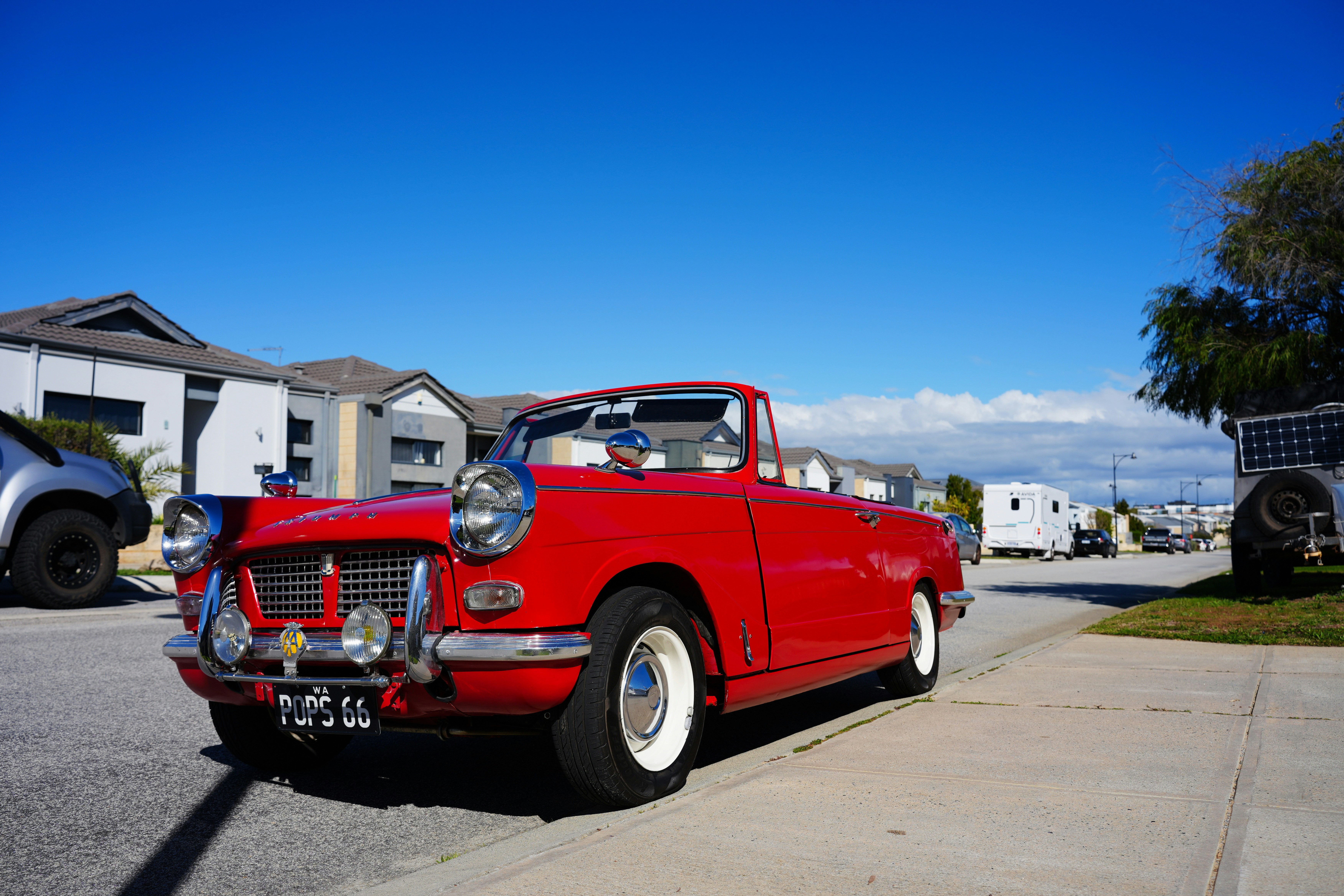 Red Roadster Restored: A Classic Convertible in a sunlit suburban street