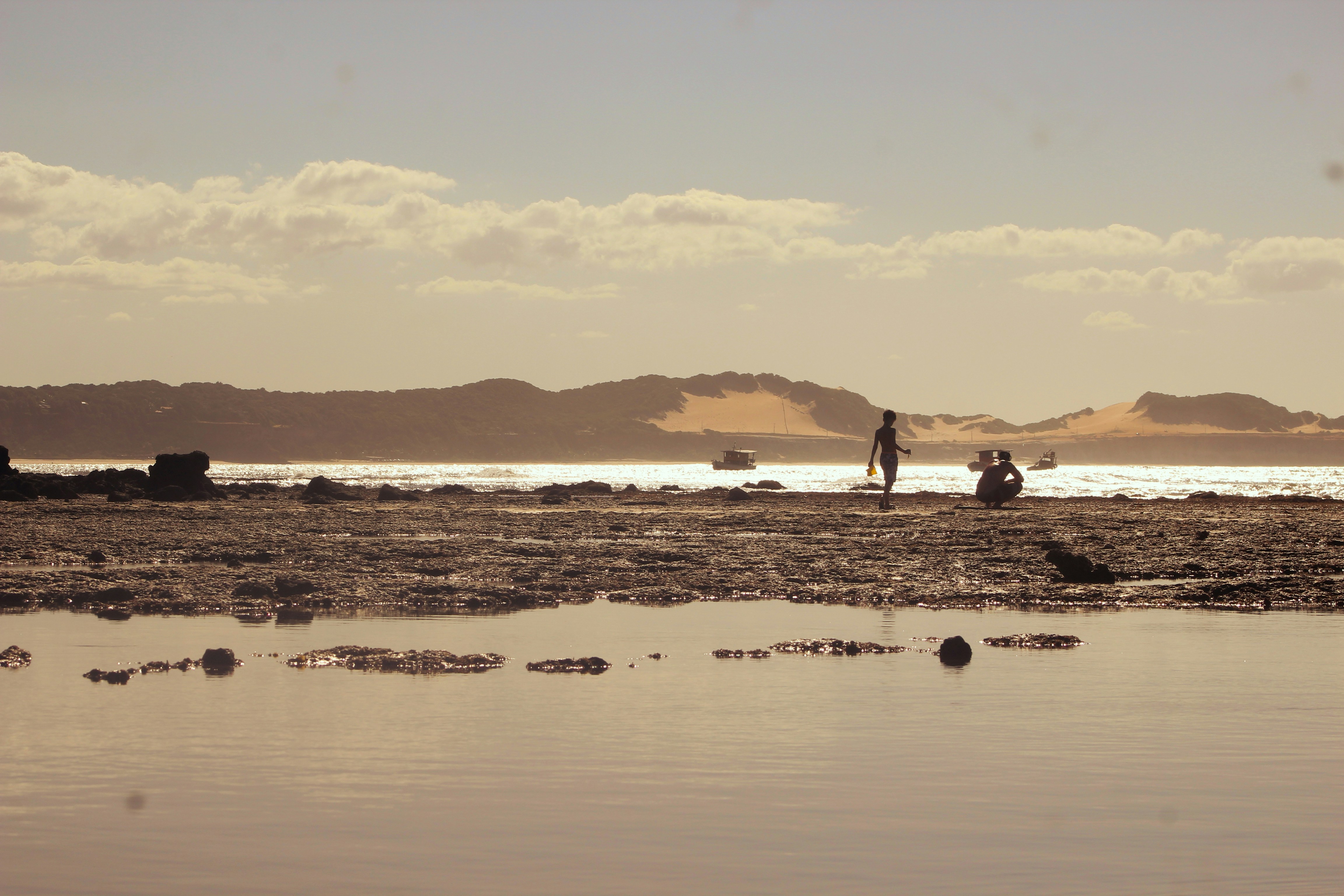 Silhouetted Beach Figures at Sunset Over Tidal Flats